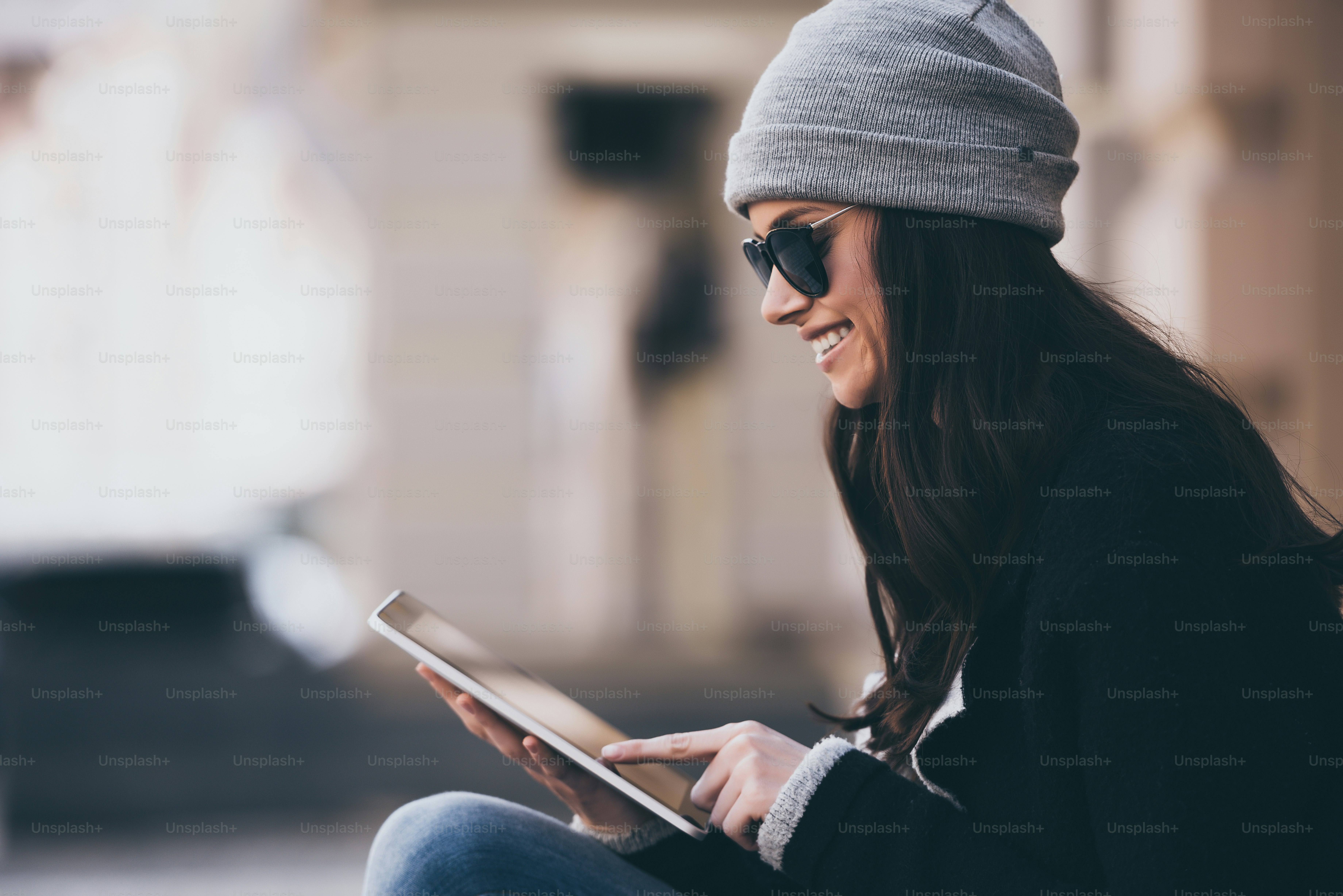 Side view of beautiful young woman in sunglasses using her digital ...