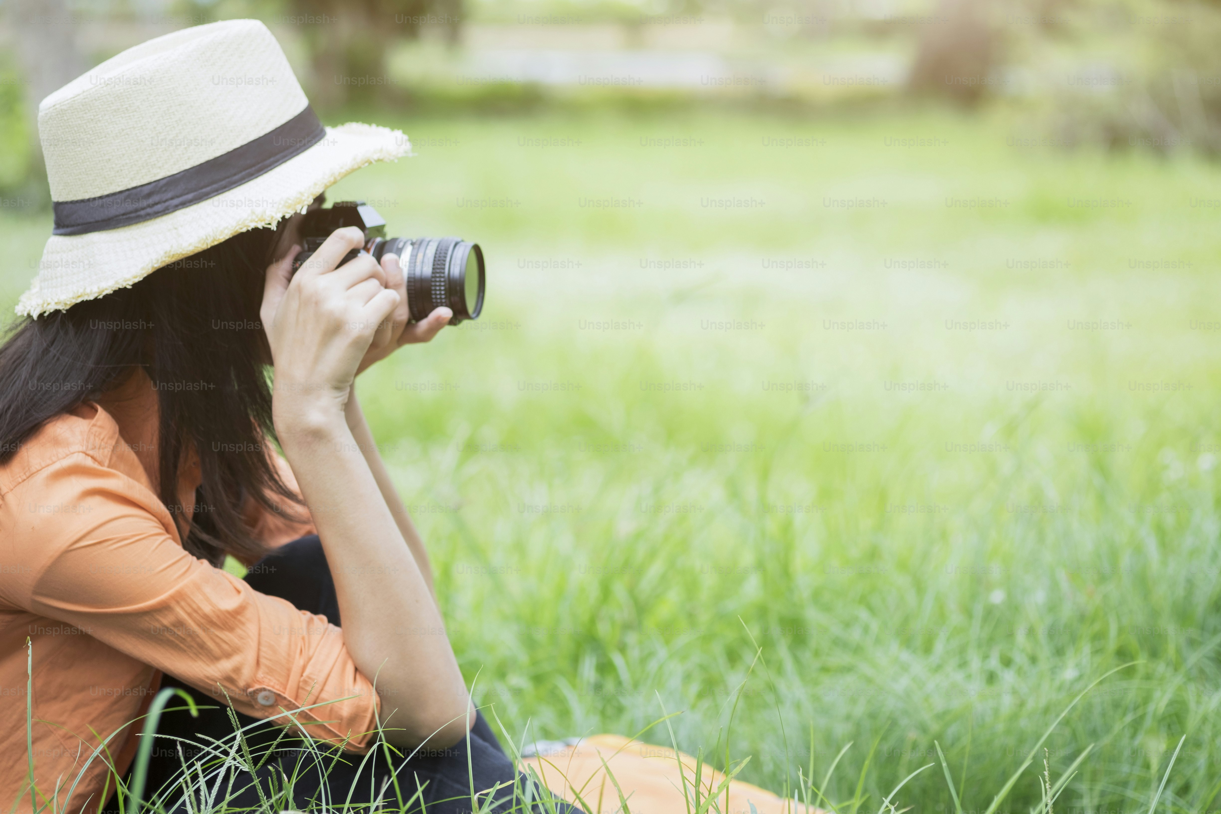Young woman using a camera to take photo outdoors at the park. photo ...