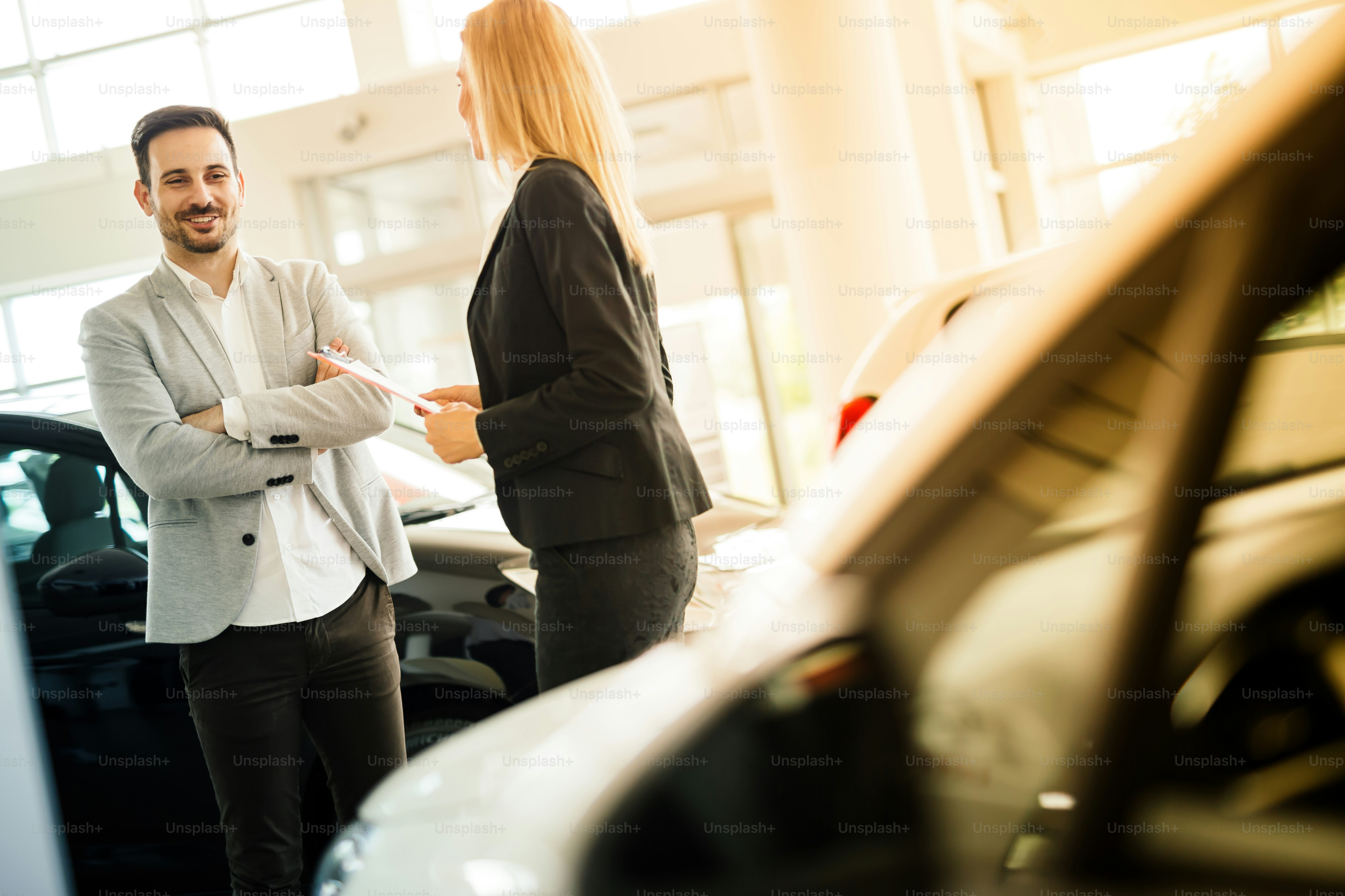 Salesperson showing vehicle to potential customer in dealership photo ...