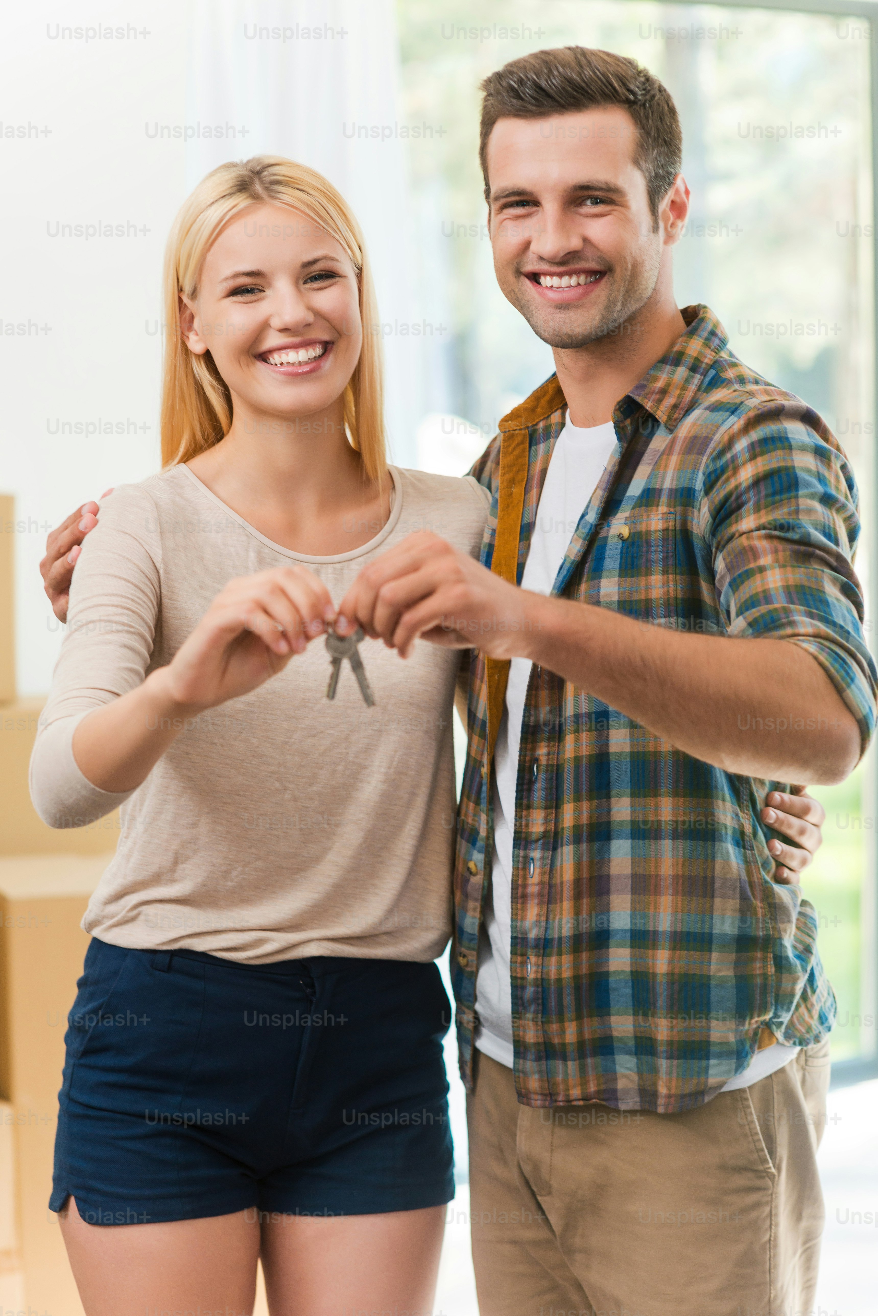 Beautiful young loving couple holding keys and smiling while standing ...