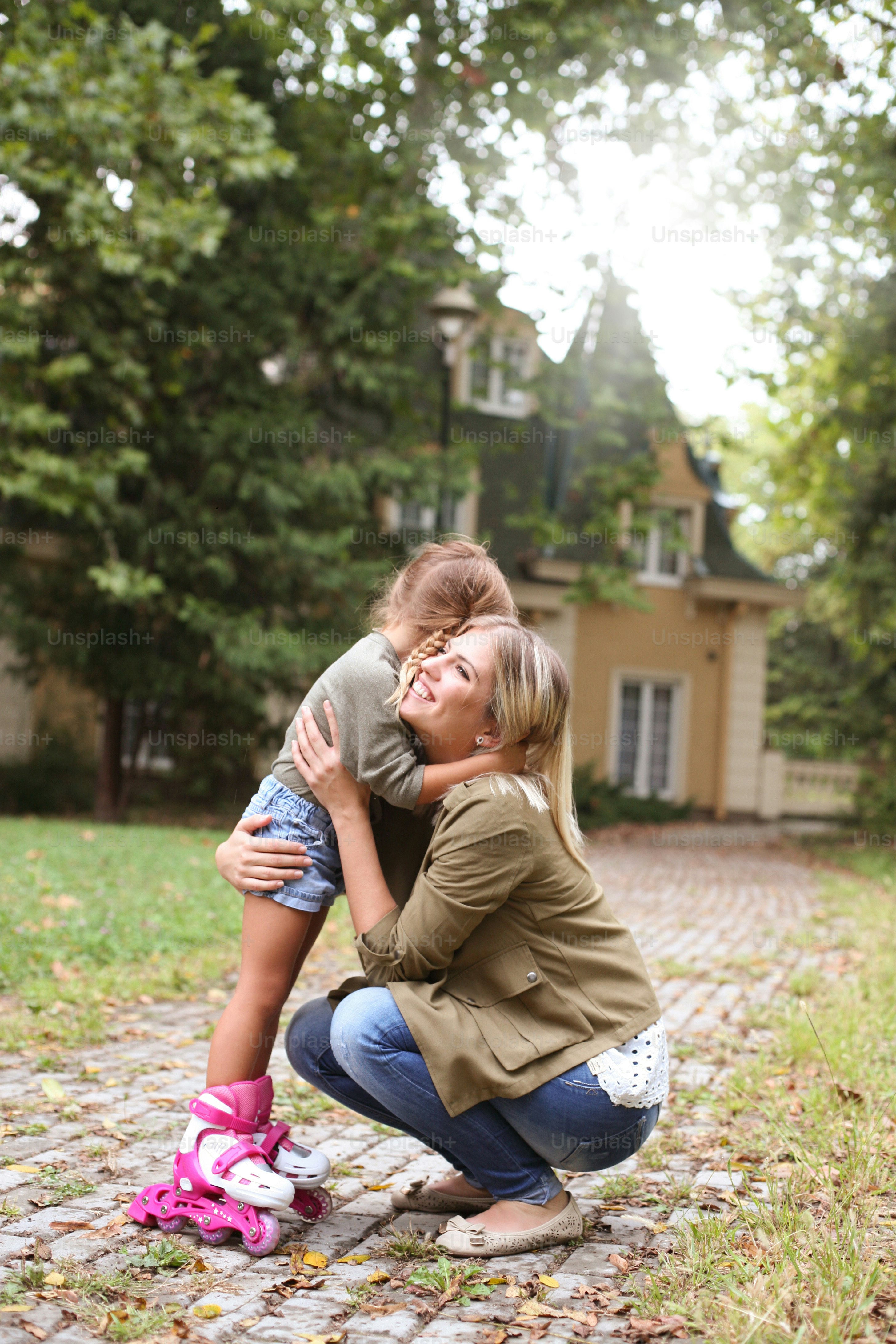 Foto zum Thema Kleines Mädchen umarmt ihre Mutter nach dem Inlineskaten ...