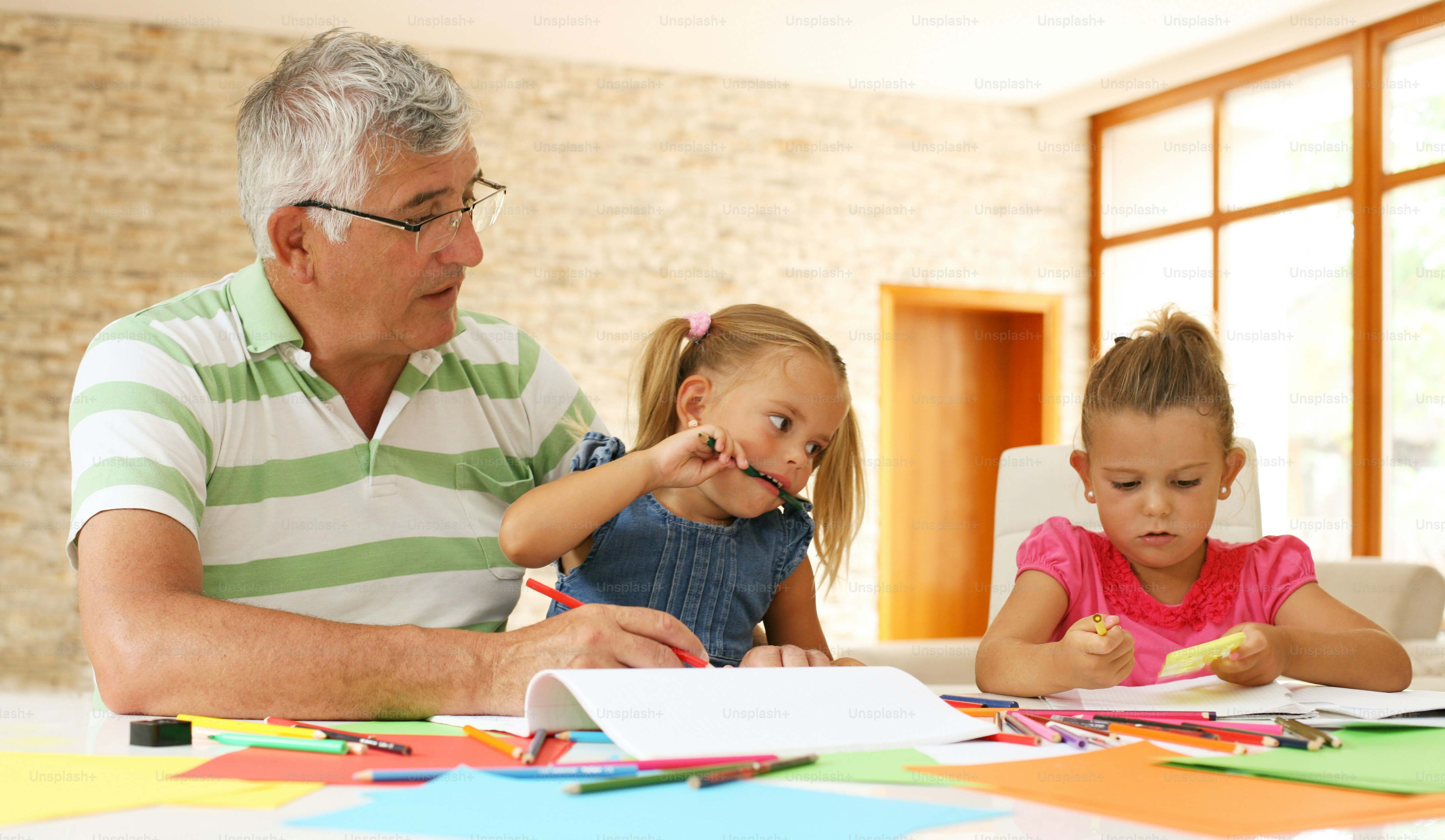 Private class. Senior man working homework with two little girls. photo ...