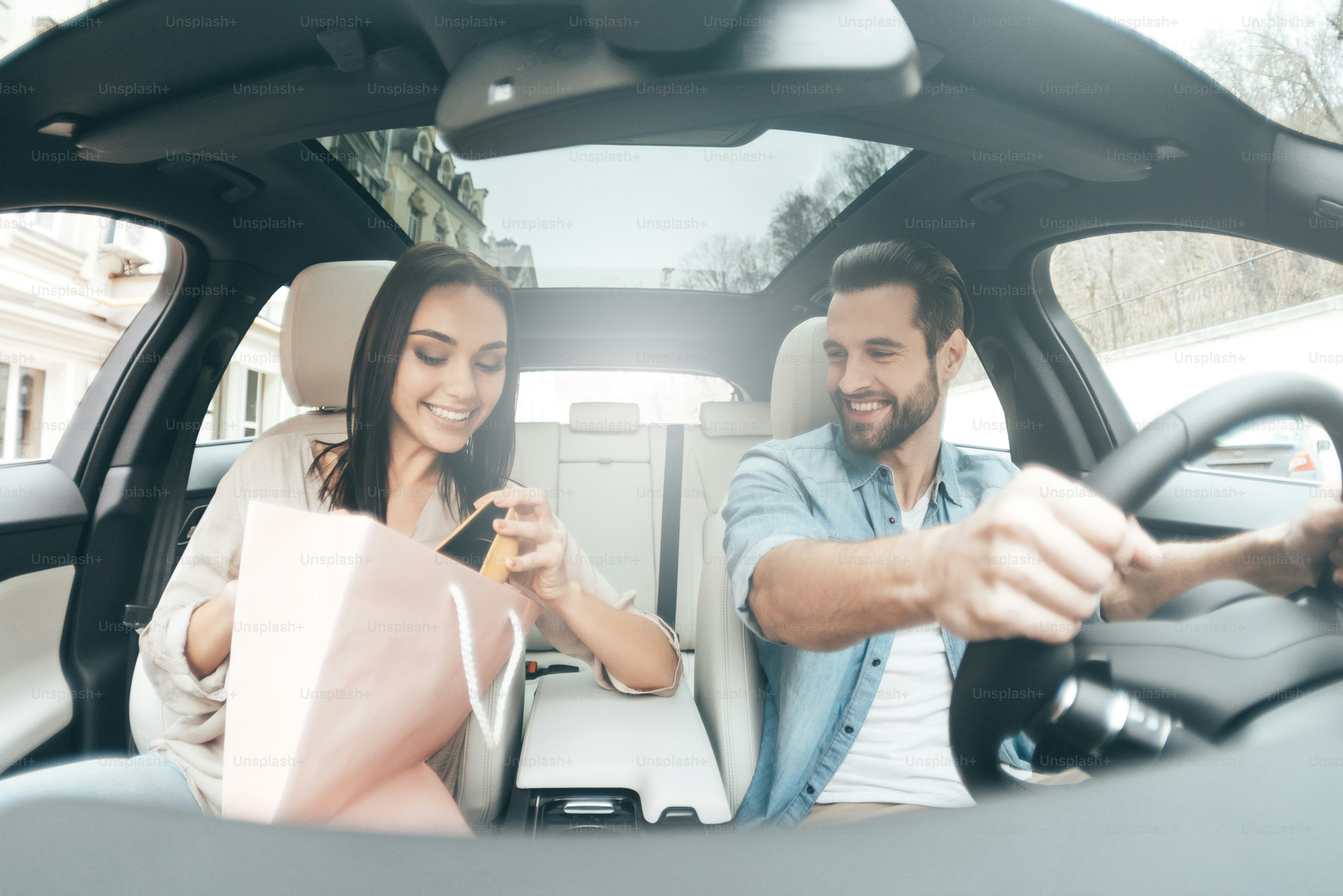 Young beautiful couple sitting on the front passenger seats and smiling ...
