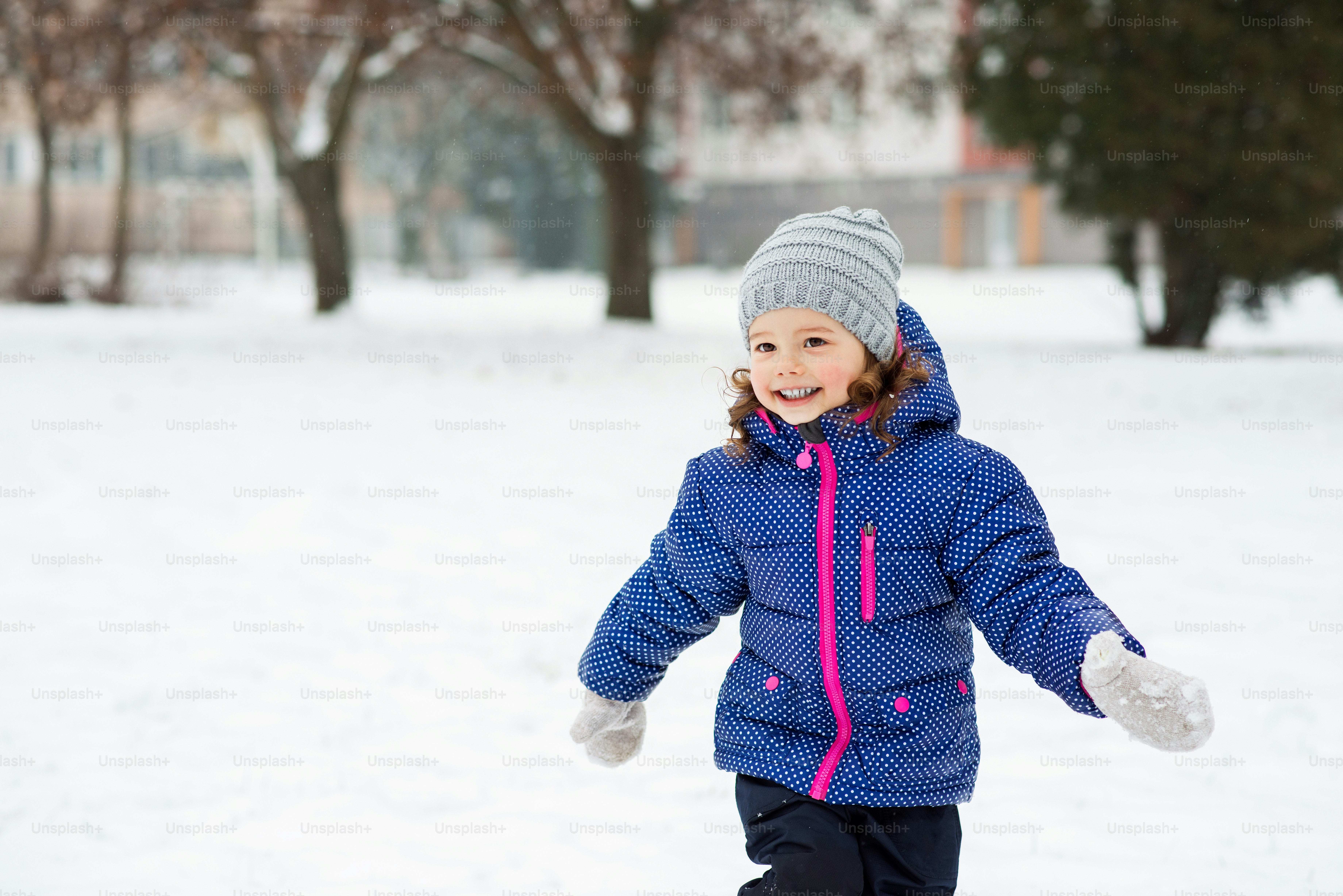 Cute little girl in blue jacket and knitted hat playing outside in ...