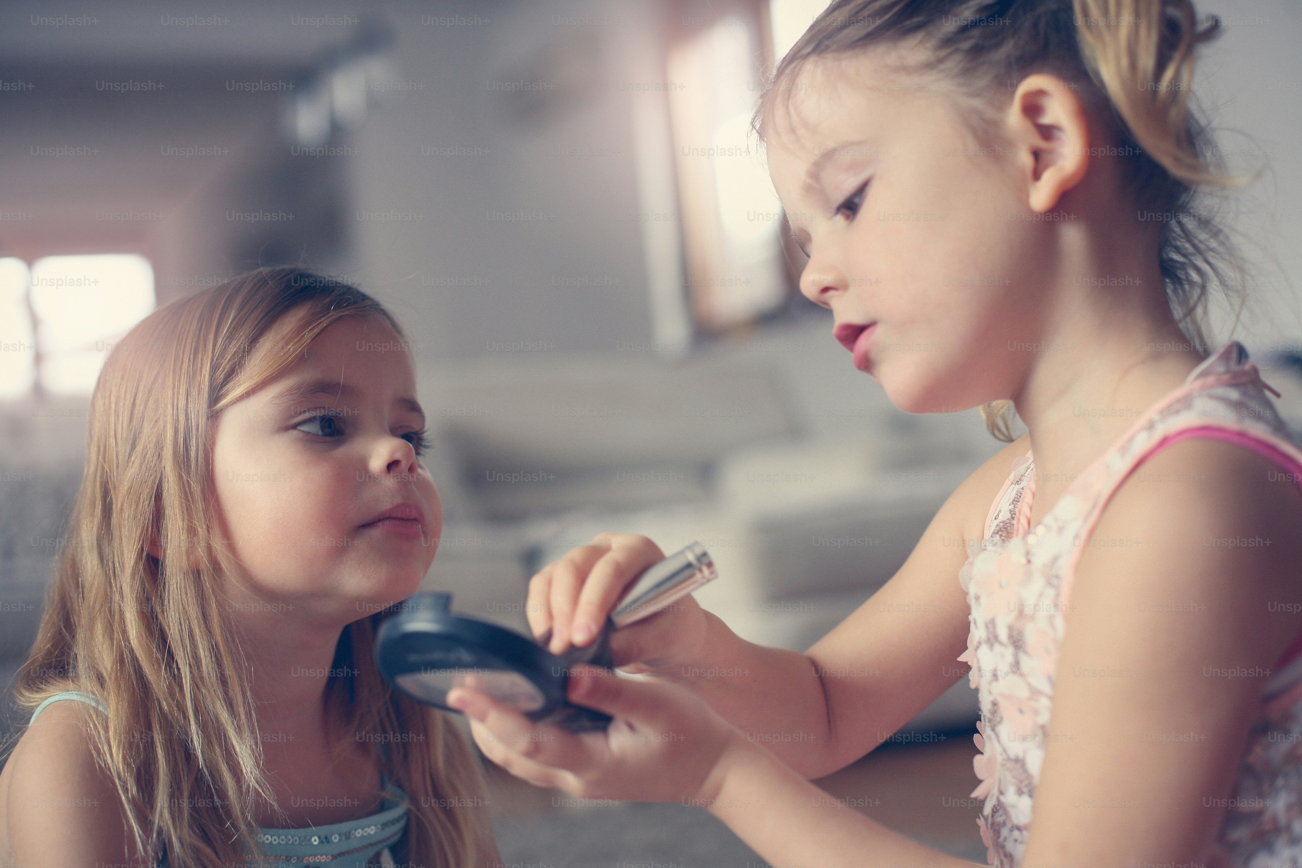 Two little girl helping each other to put shadows on their face. photo ...