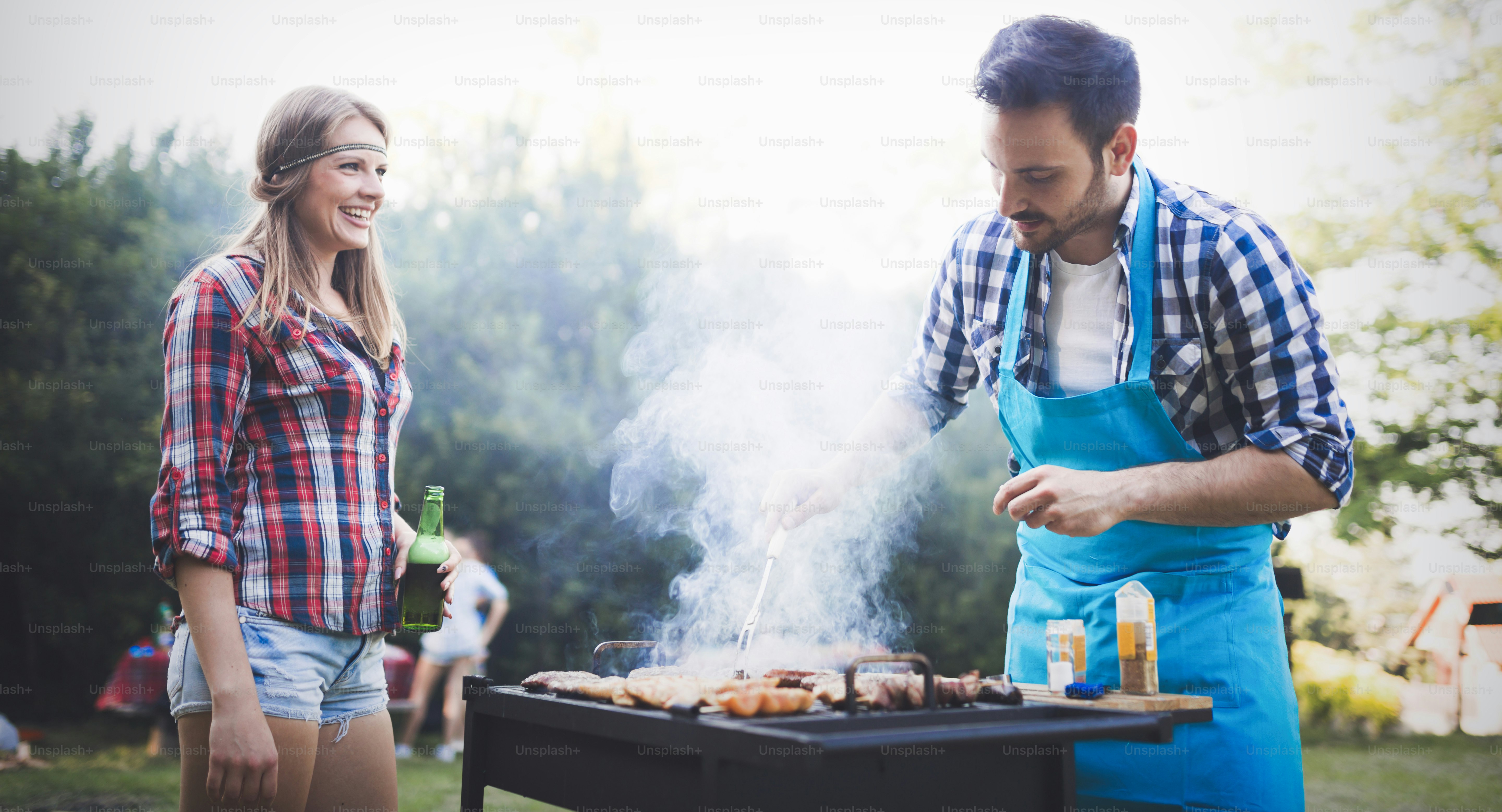 Happy friends grilling meat and enjoying barbecue party outdoors photo ...