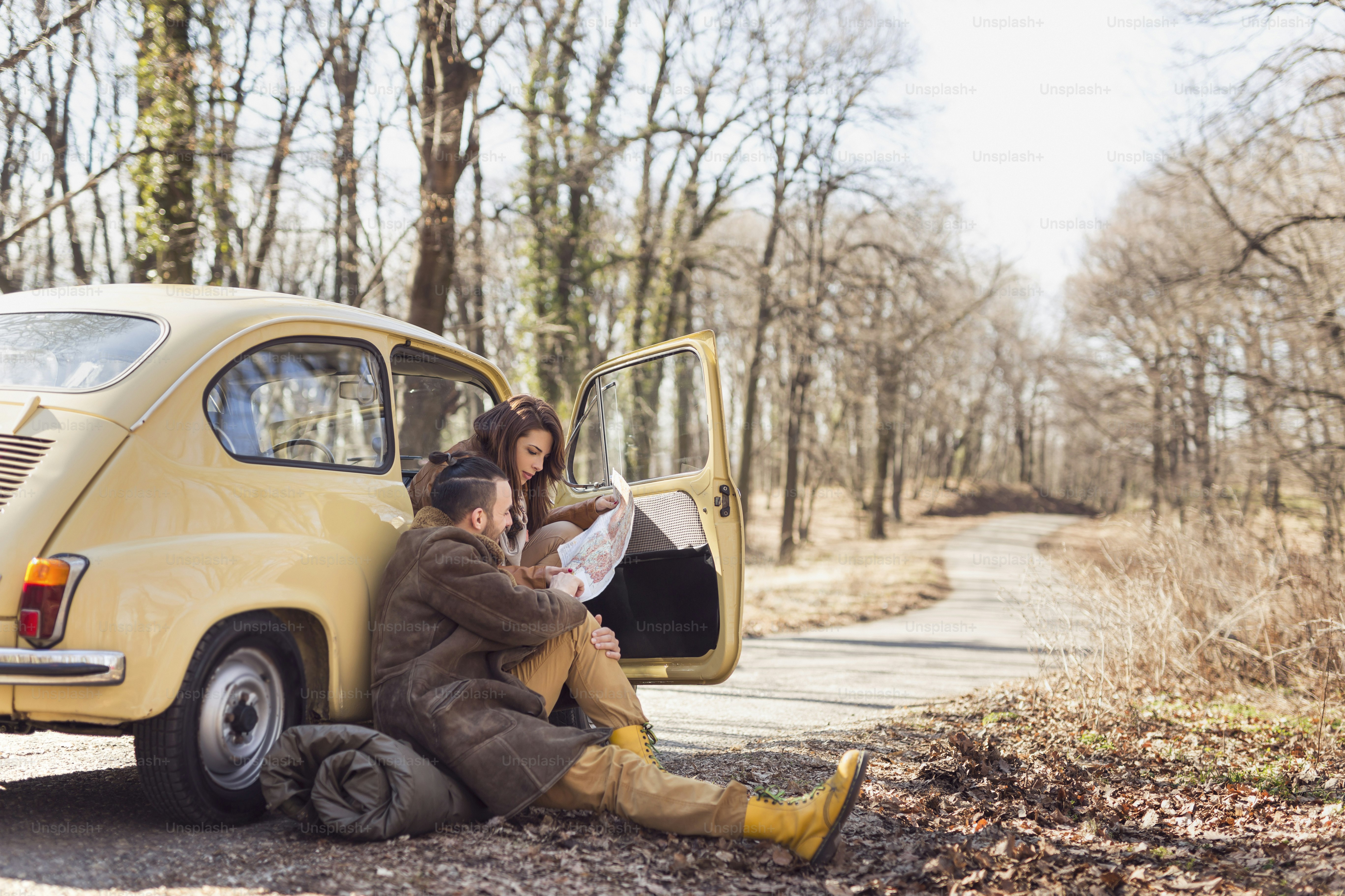 Young couple in love taking a break on their road trip, sitting by the ...
