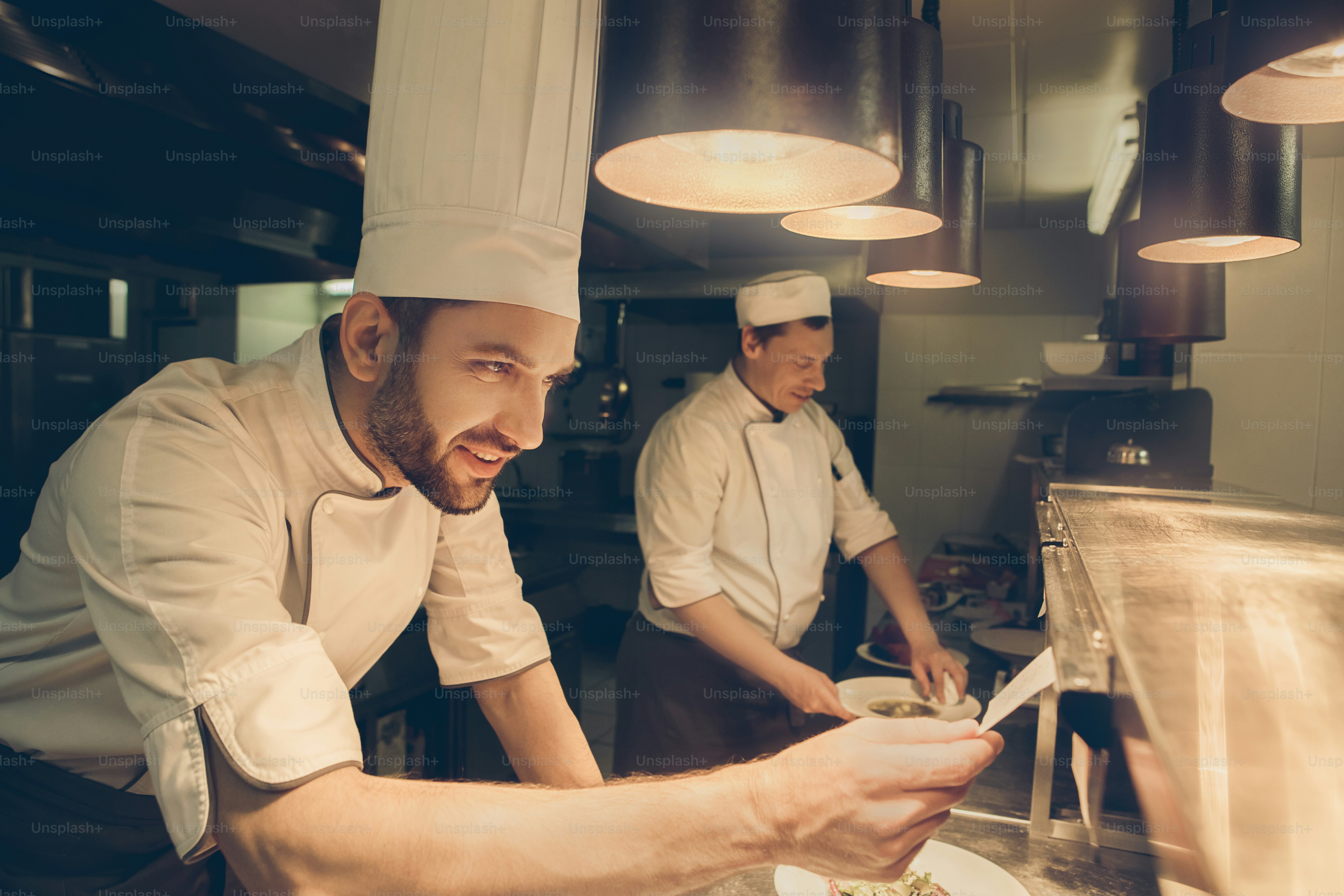Male japanese restaurant chef cooking in the kitchen reading order ...