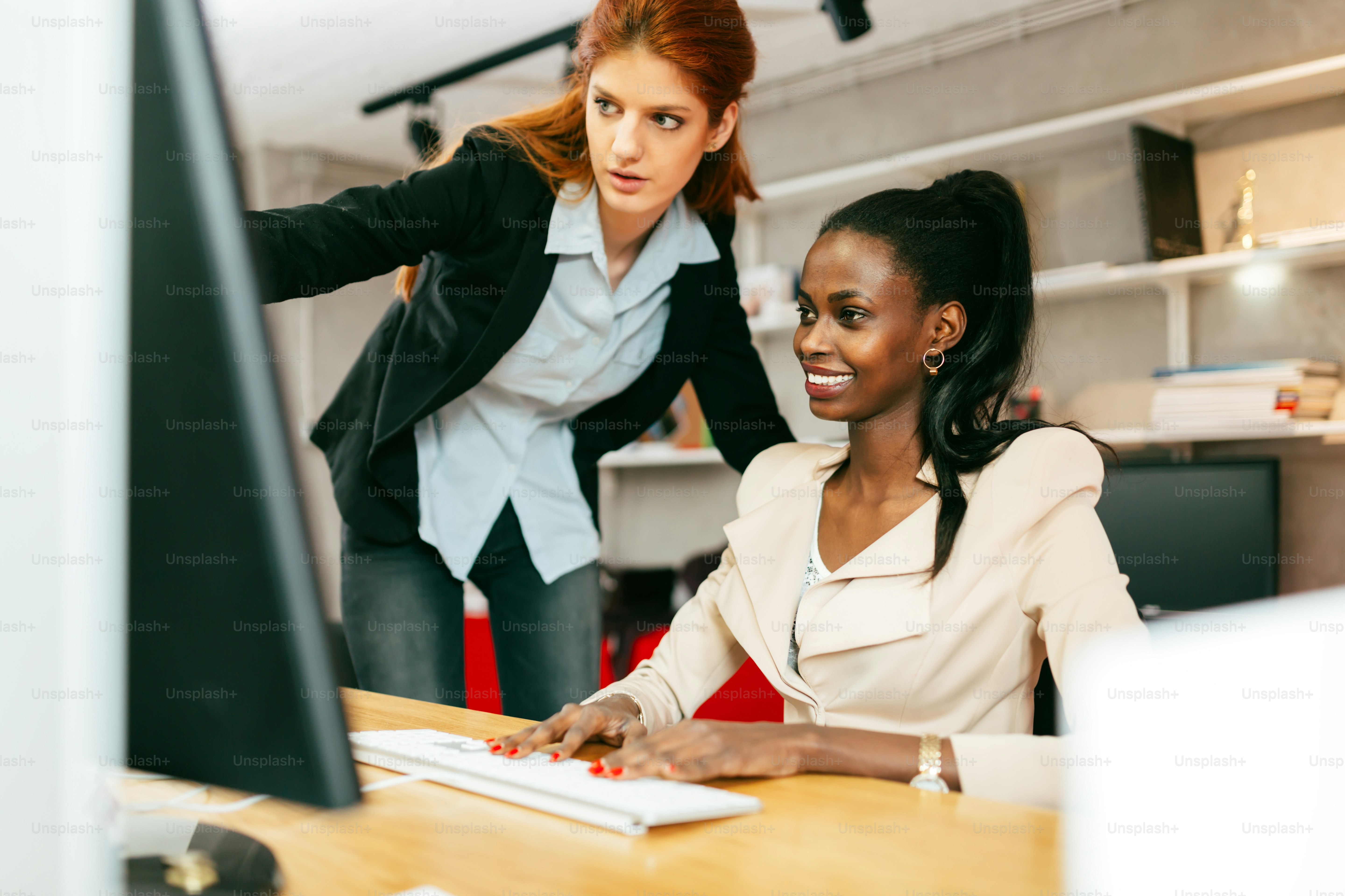 Busiensswoman advising colleague in office during work photo – Indoors ...