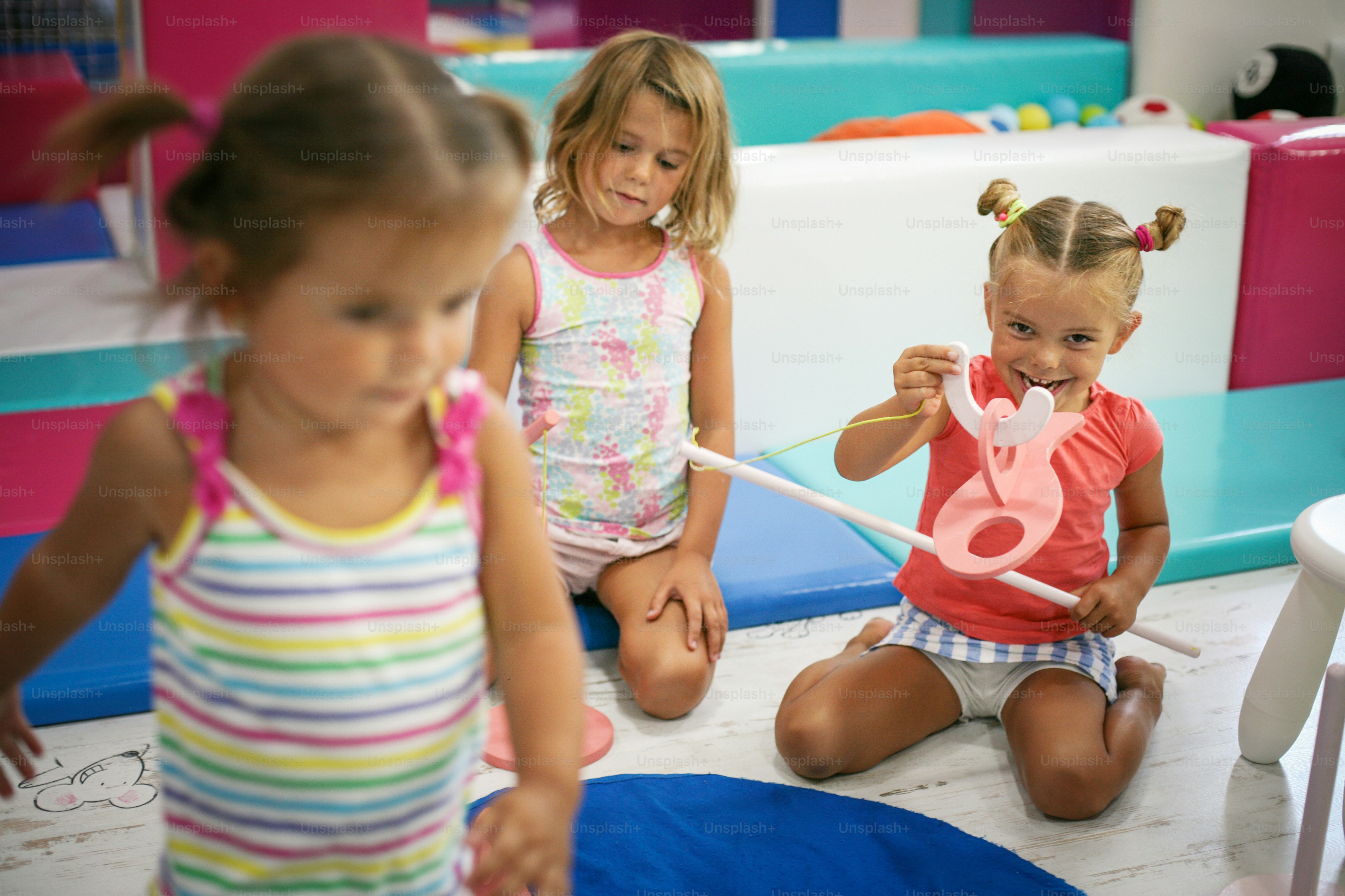 Three little girls in playground. Caucasian girls playing on floor ...