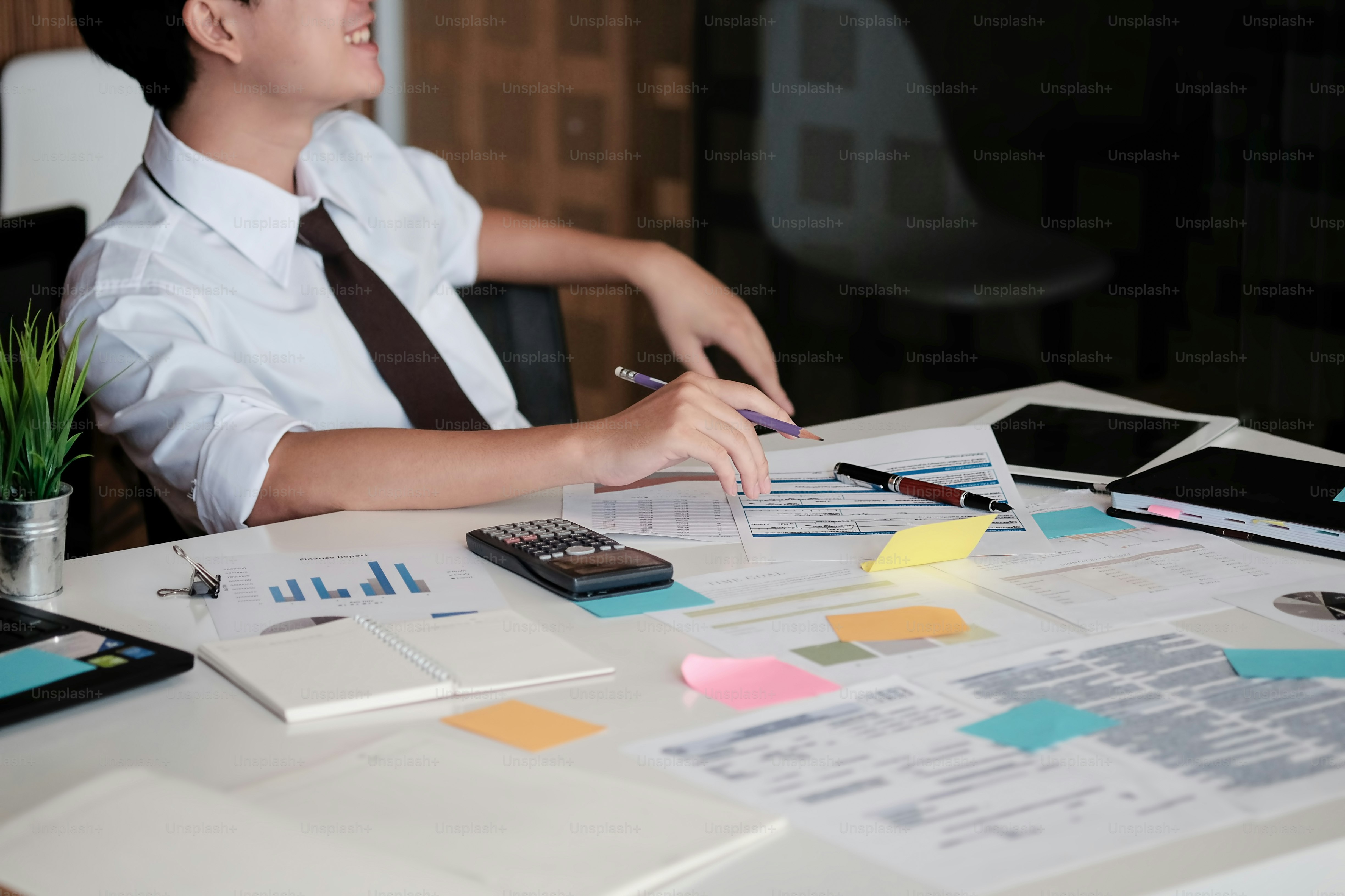 Joven hombre de negocios asiático sentado en la oficina y sonrisa en la cara, enfoque selectivo ...