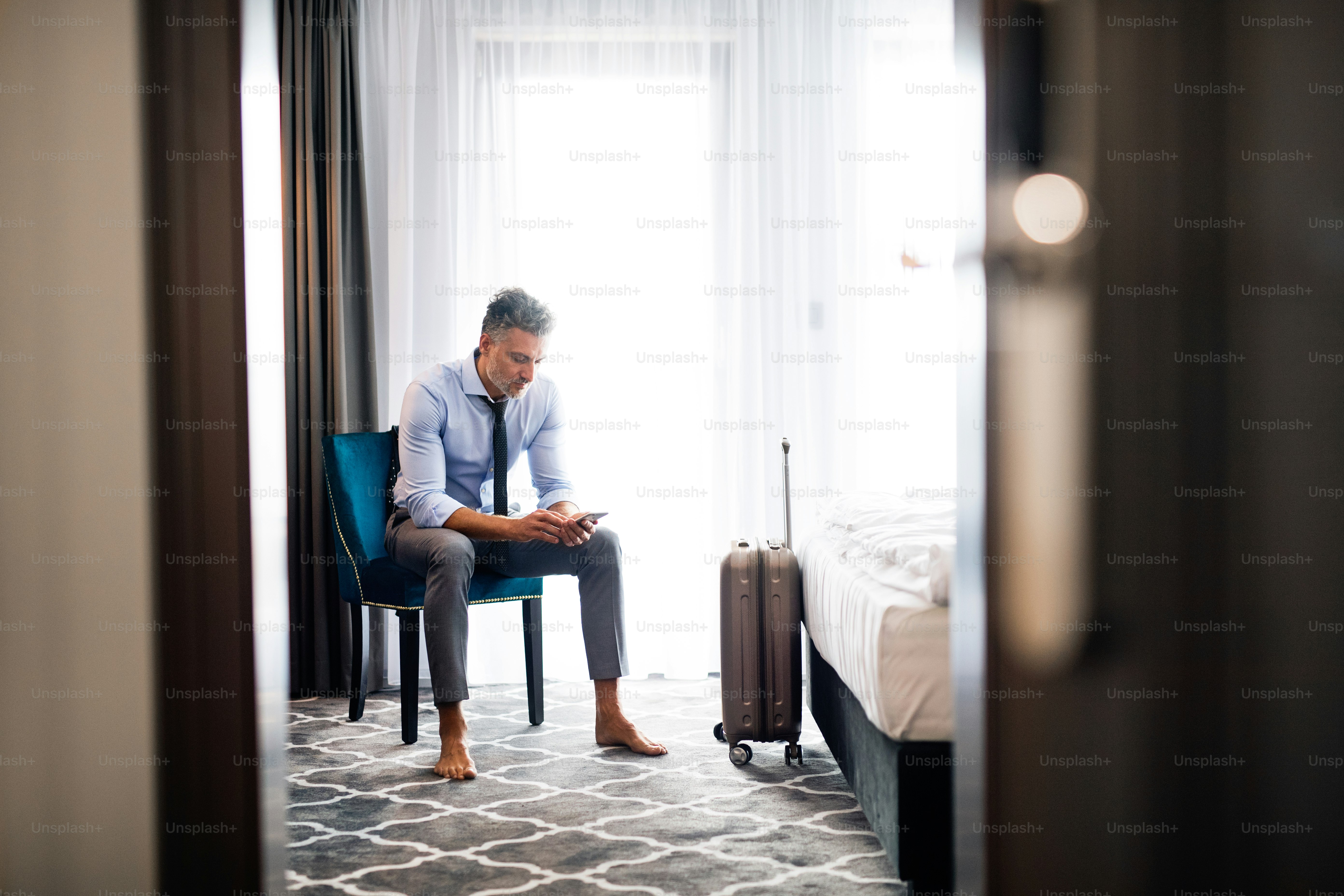 Mature businessman standing at the big windows in a hotel. Man looking ...