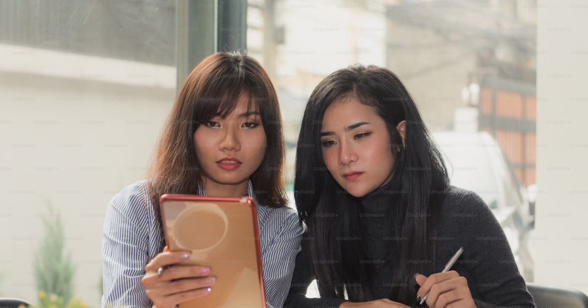 일대일 회의 카페의 테이블에 앉아 있는 두 명의 젊은 비즈니스 여성 소녀는 노트북 화면에 동료 정보를 보여줍니다 스마트폰