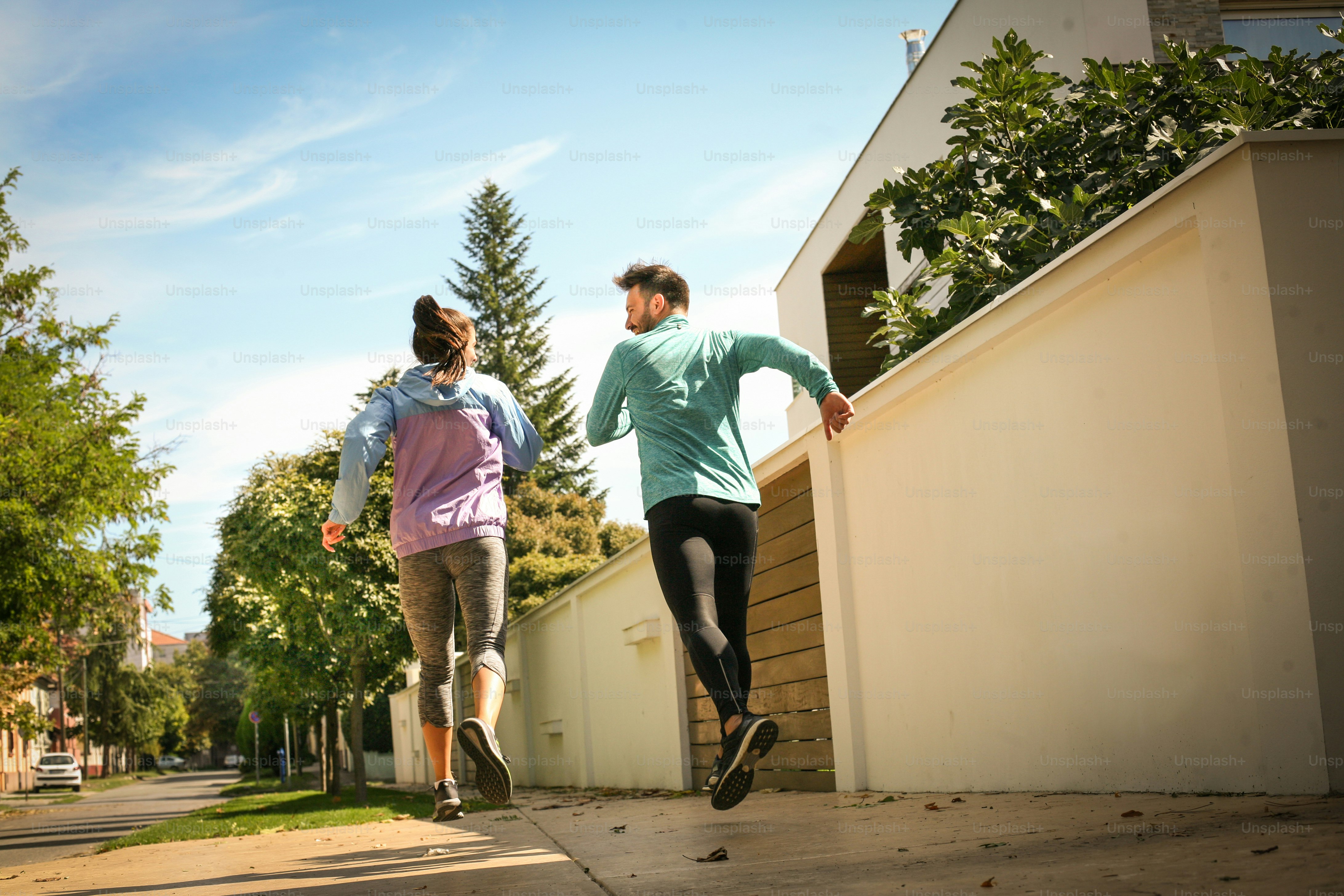 Young couple running together city streets. Back view. photo – Jogging ...