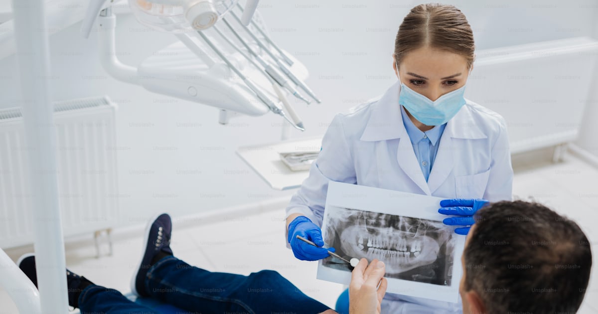 치아 염증 전문 숙련 된 여성 치과 의사가 Xray 사진을 들고 진단을 설명하면서 환자를 바라보고 있습니다 사진