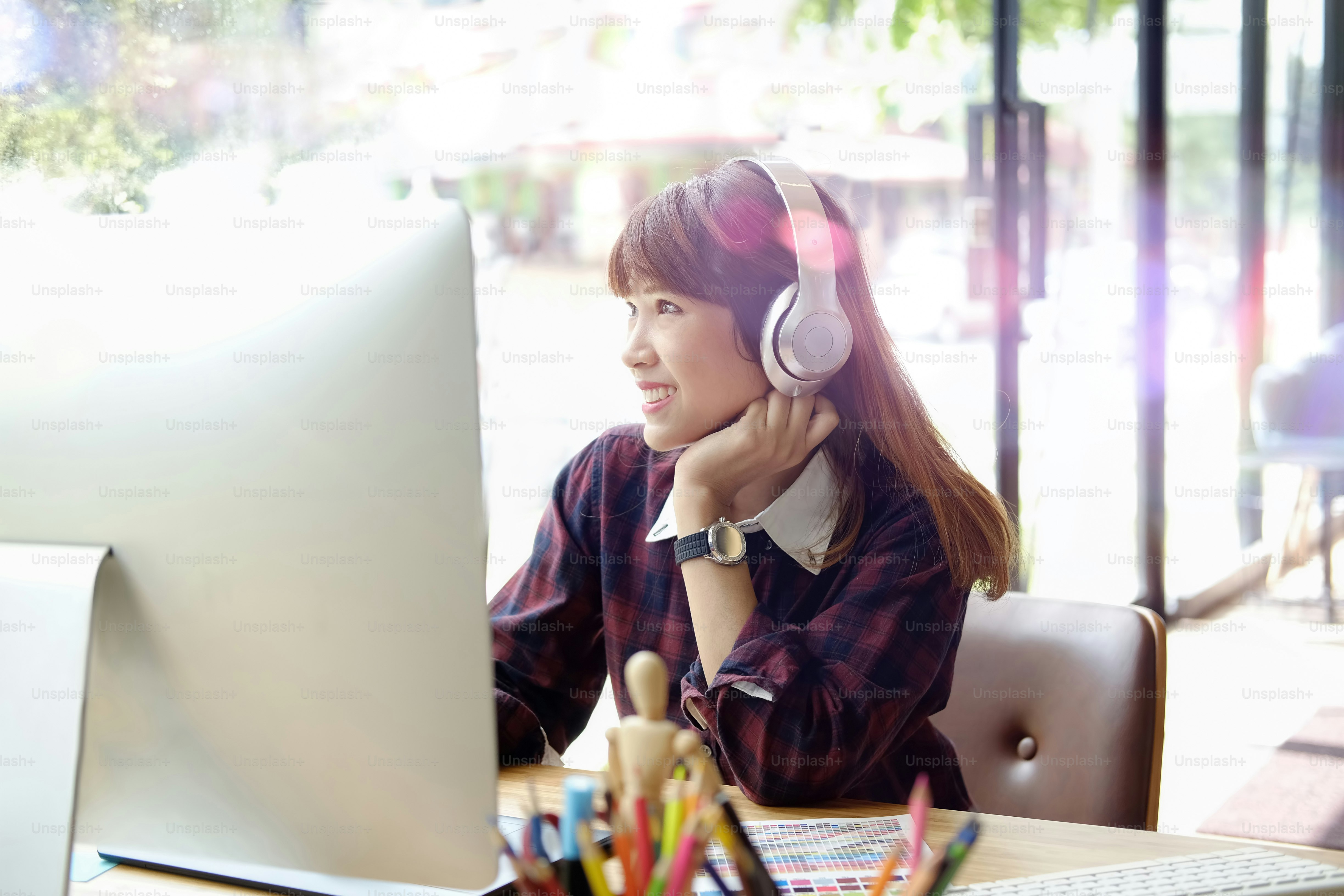 Happy woman using desktop computer while listening at studio office ...