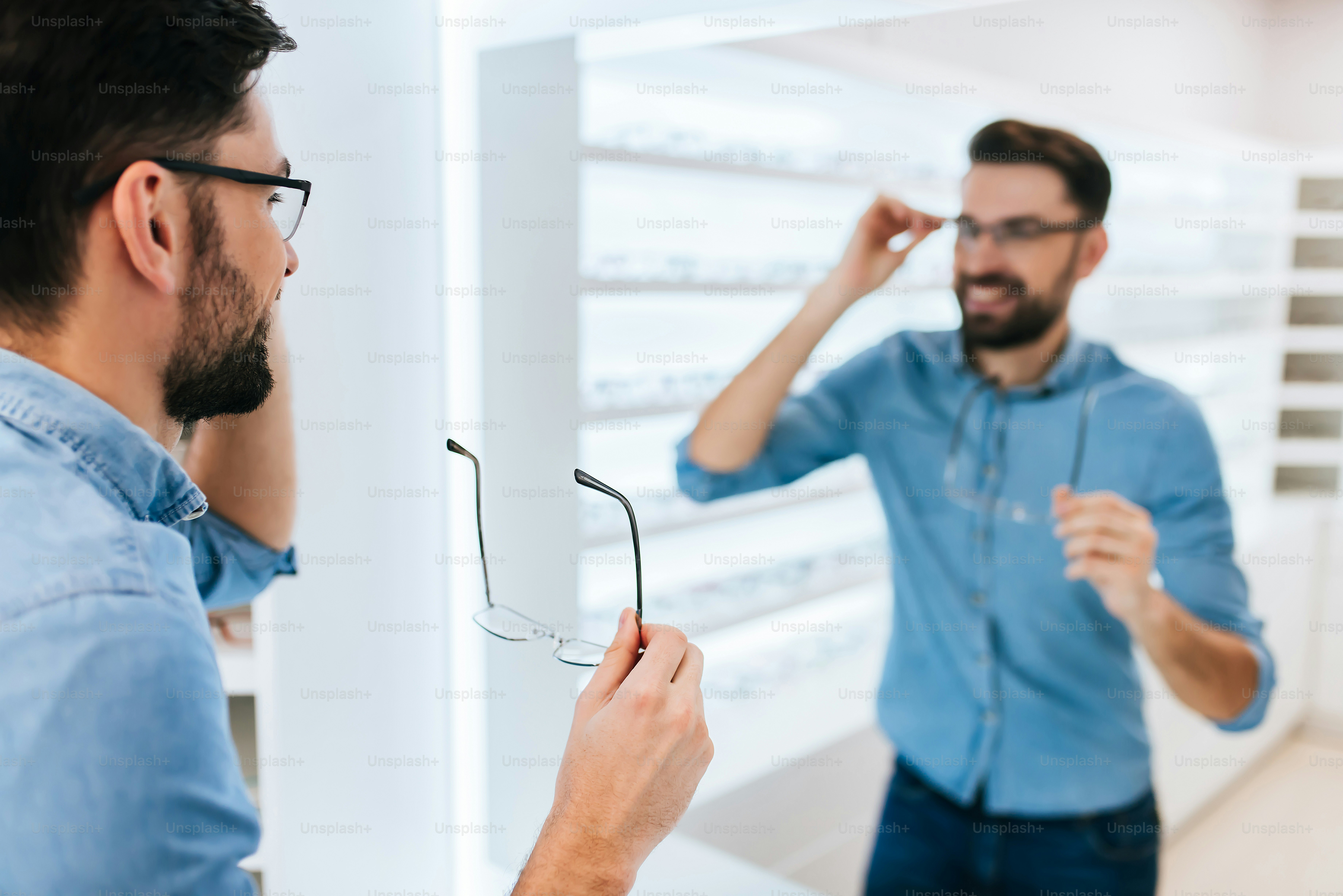 Handsome young man is choosing the most appropriate eyeglasses in ...