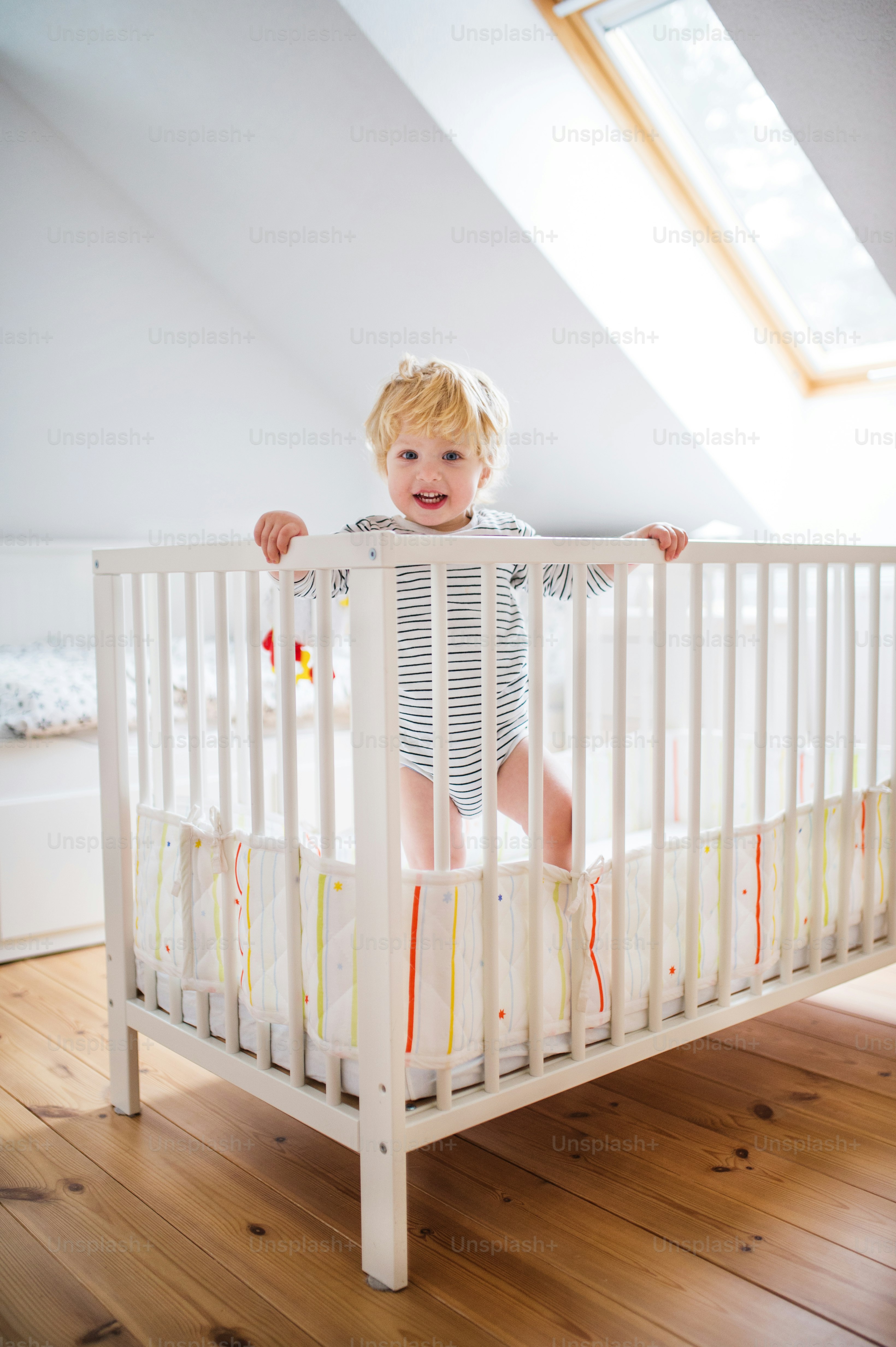 Cute happy toddler boy standing in a cot at home. photo – Inside of ...