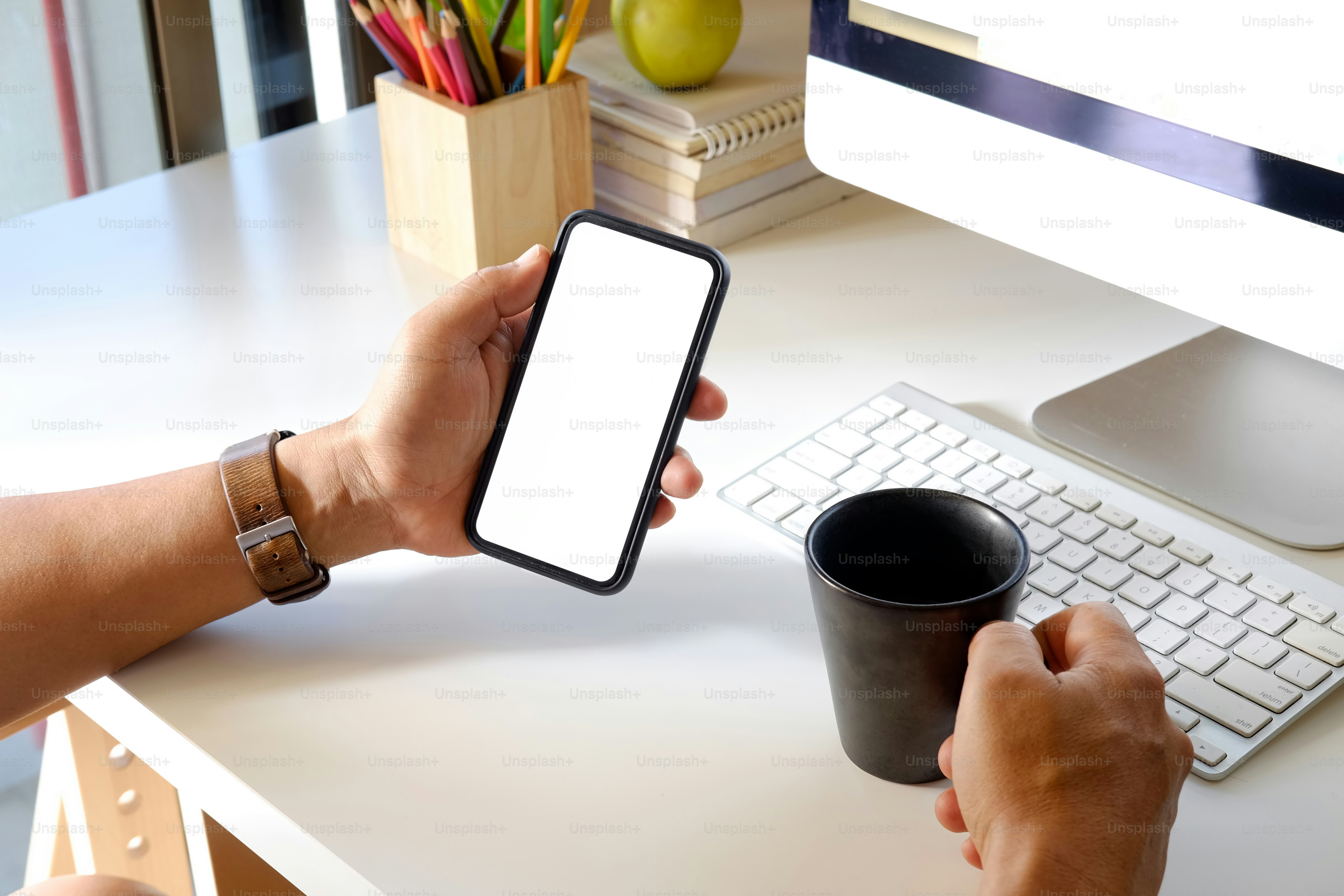 Cropped shot of man holding blank screen mobile phone on desk. Screen ...