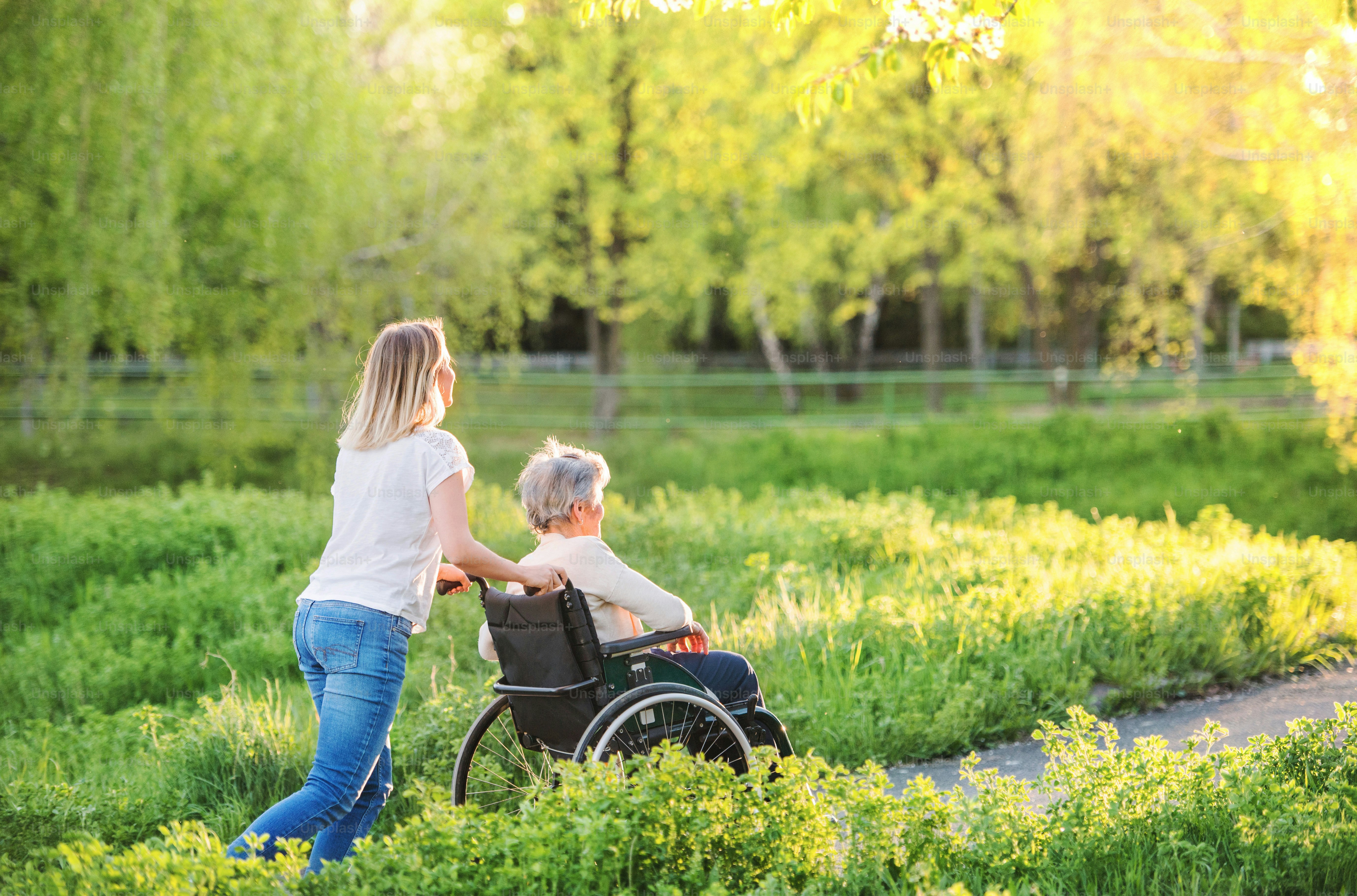 Elderly grandmother in wheelchair with an adult granddaughter outside ...