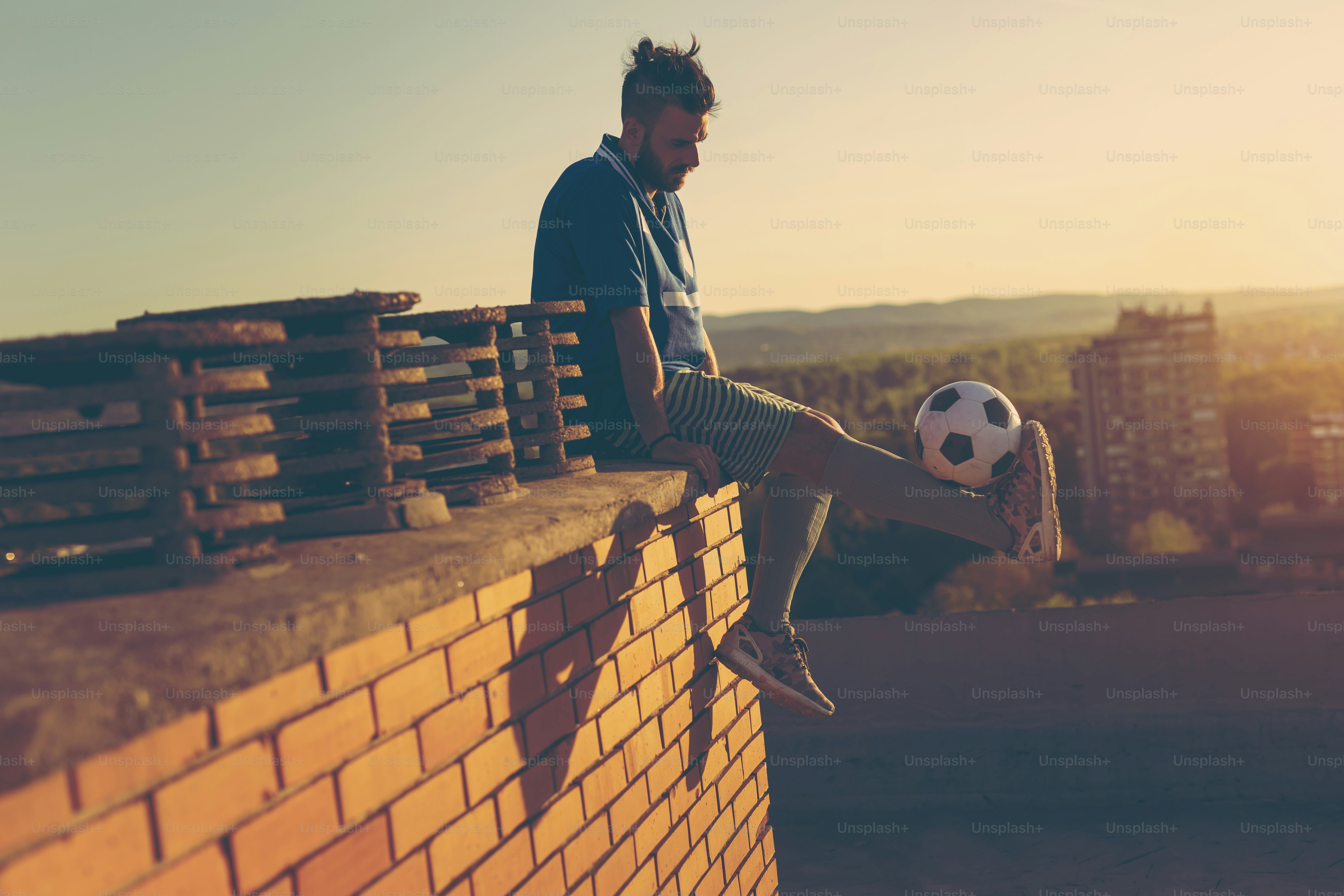 Football player on a building rooftop, sitting and relaxing after the ...