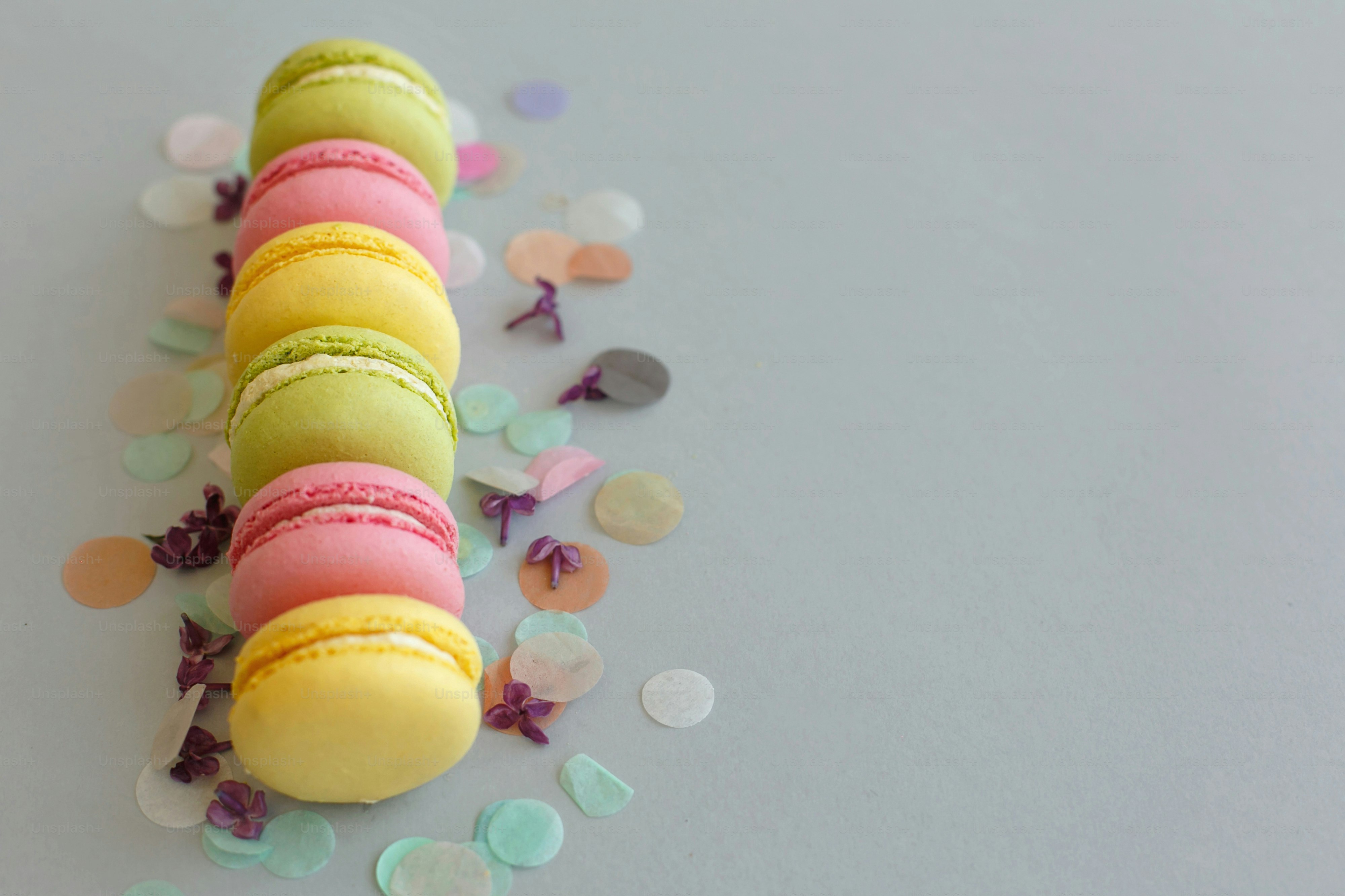 Macarons de colores sobre papel gris pastel de moda con flores lilas y ...