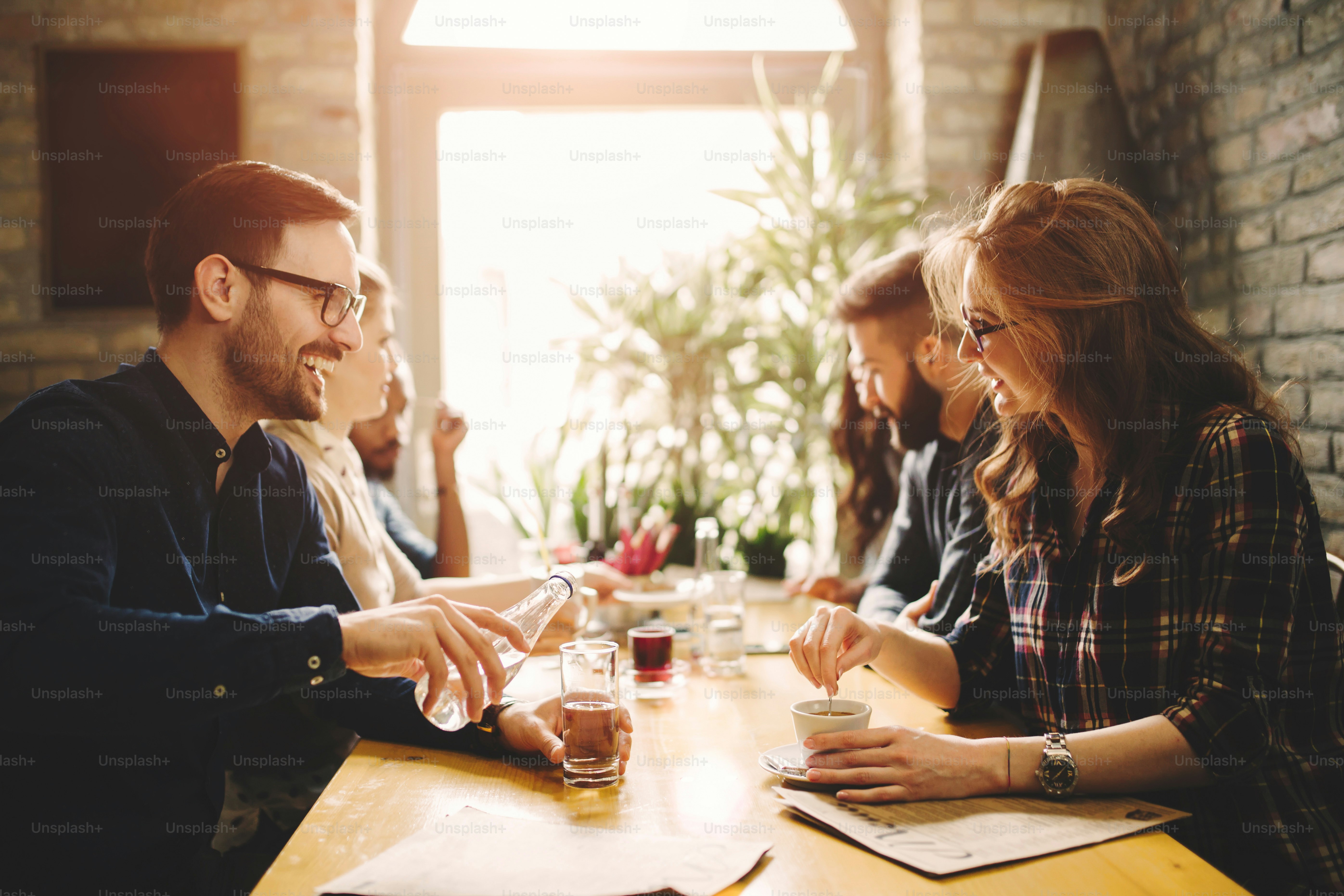 Happy young colleagues from work socializing in restaurant photo – Joy ...