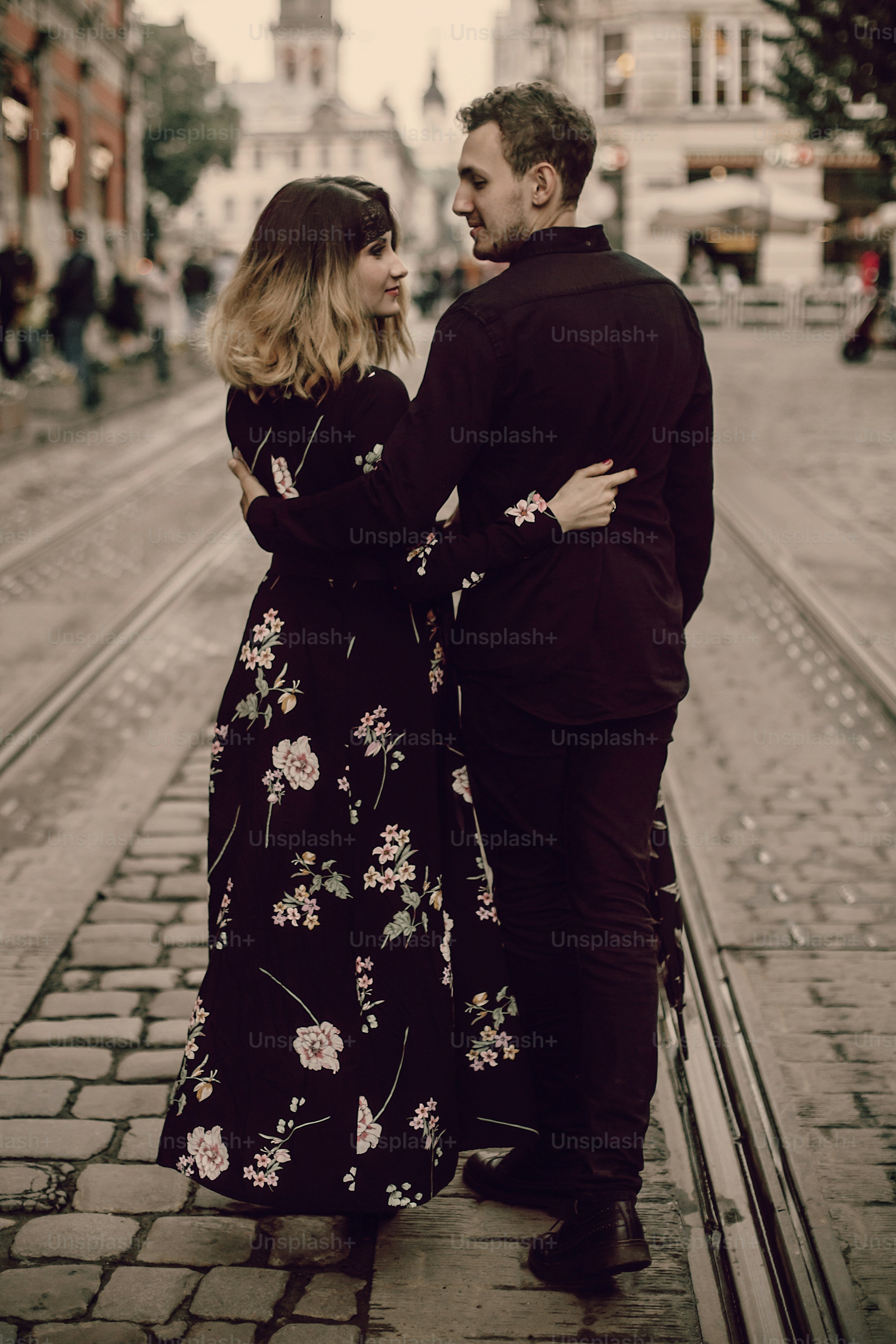 Stylish gypsy couple in love walking and hugging in evening city street ...