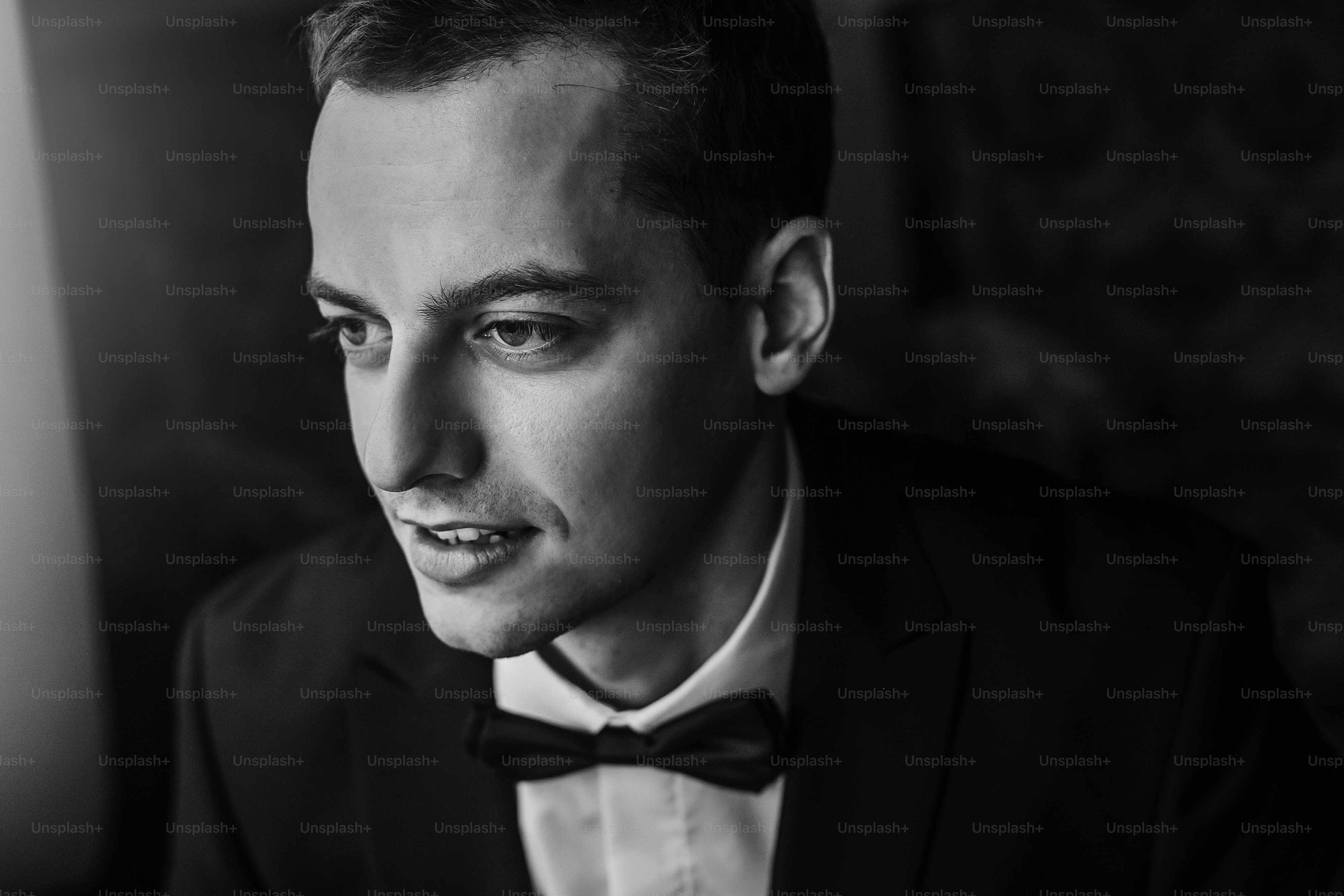 Schönes Bräutigamporträt am Morgen im Zimmer. Glücklicher Mann im Anzug ...