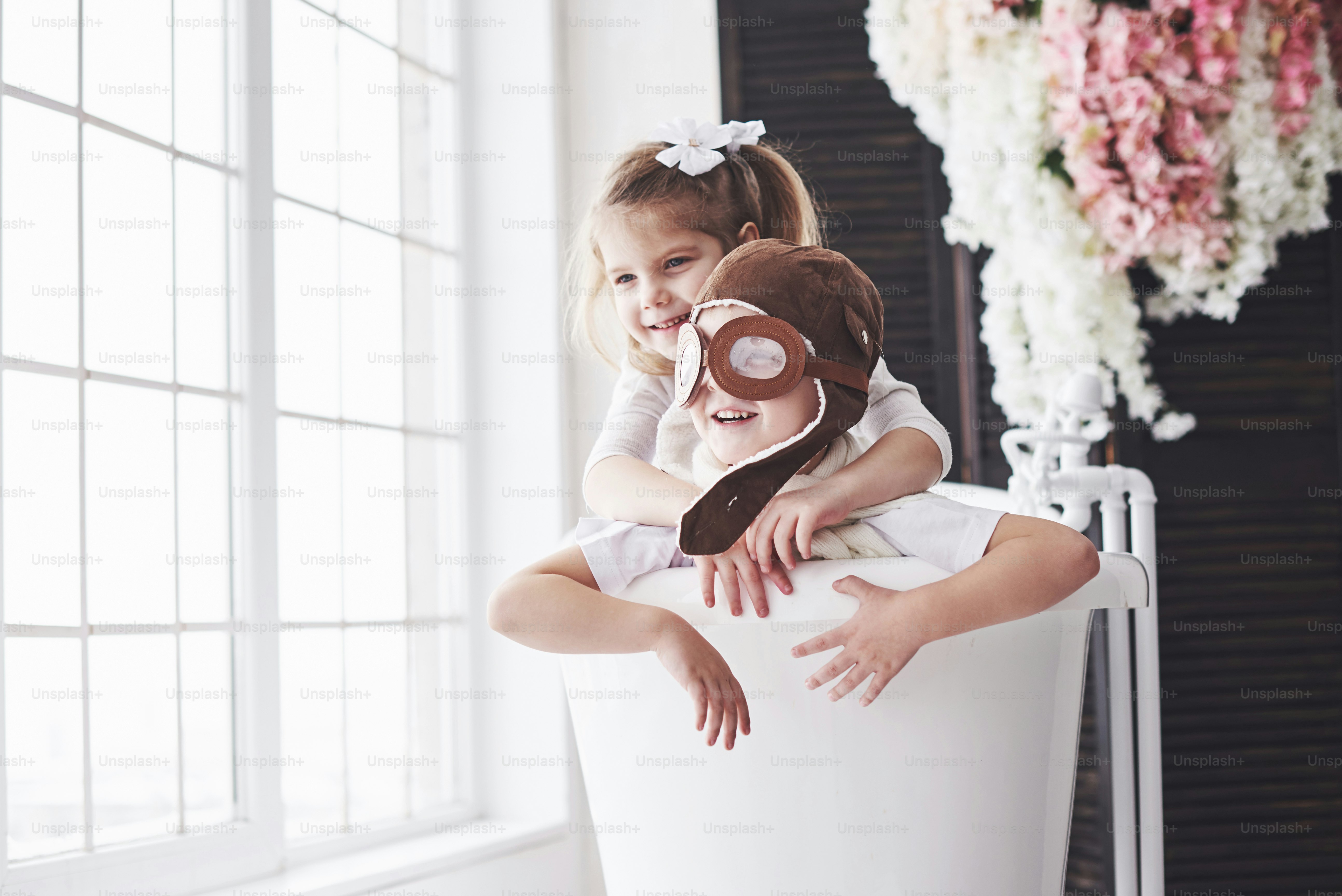 Portrait of a girl and a boy in pilot hat playing in bathroom at pilots ...