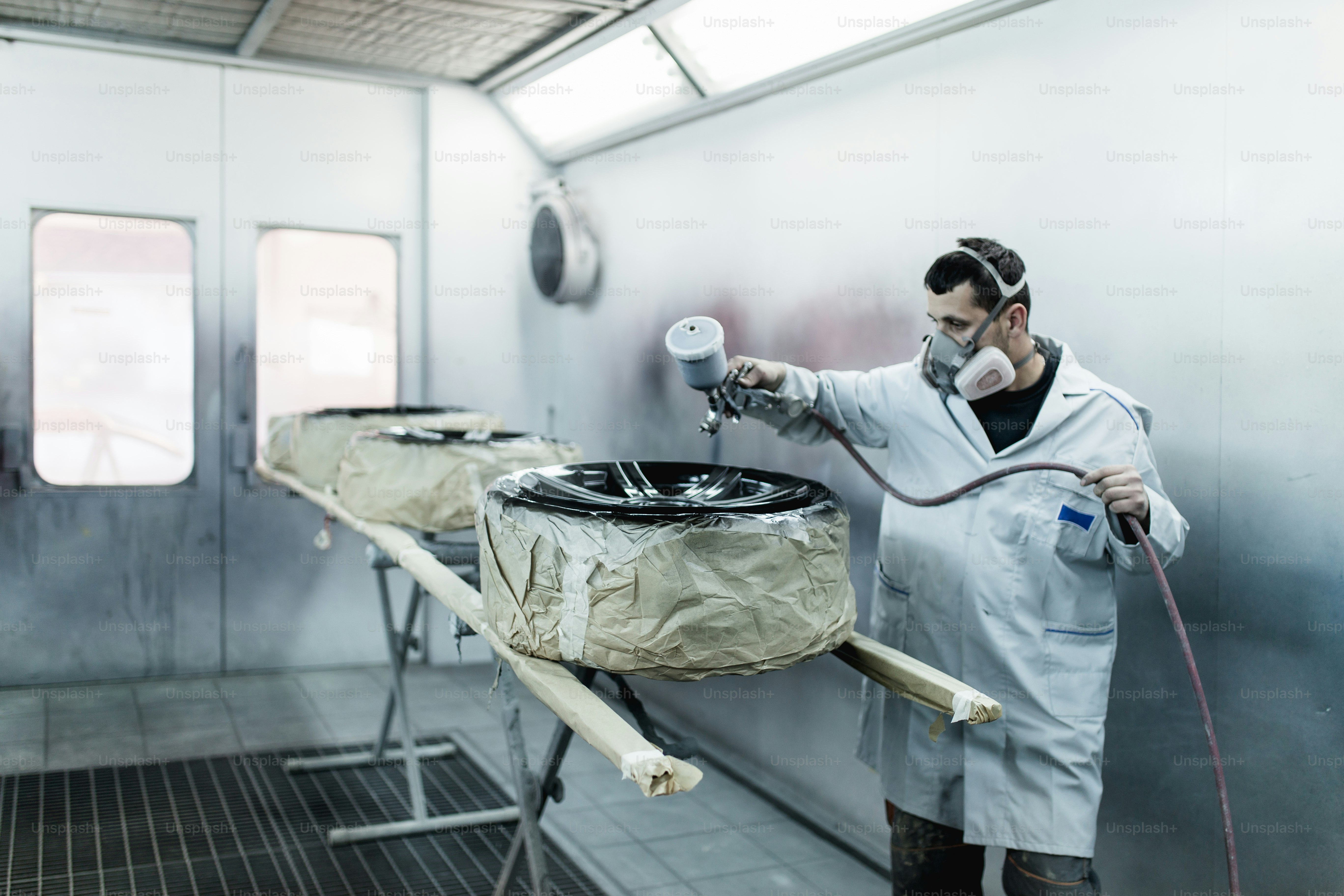 Homme avec des vêtements de protection et un masque peignant des pièces ...
