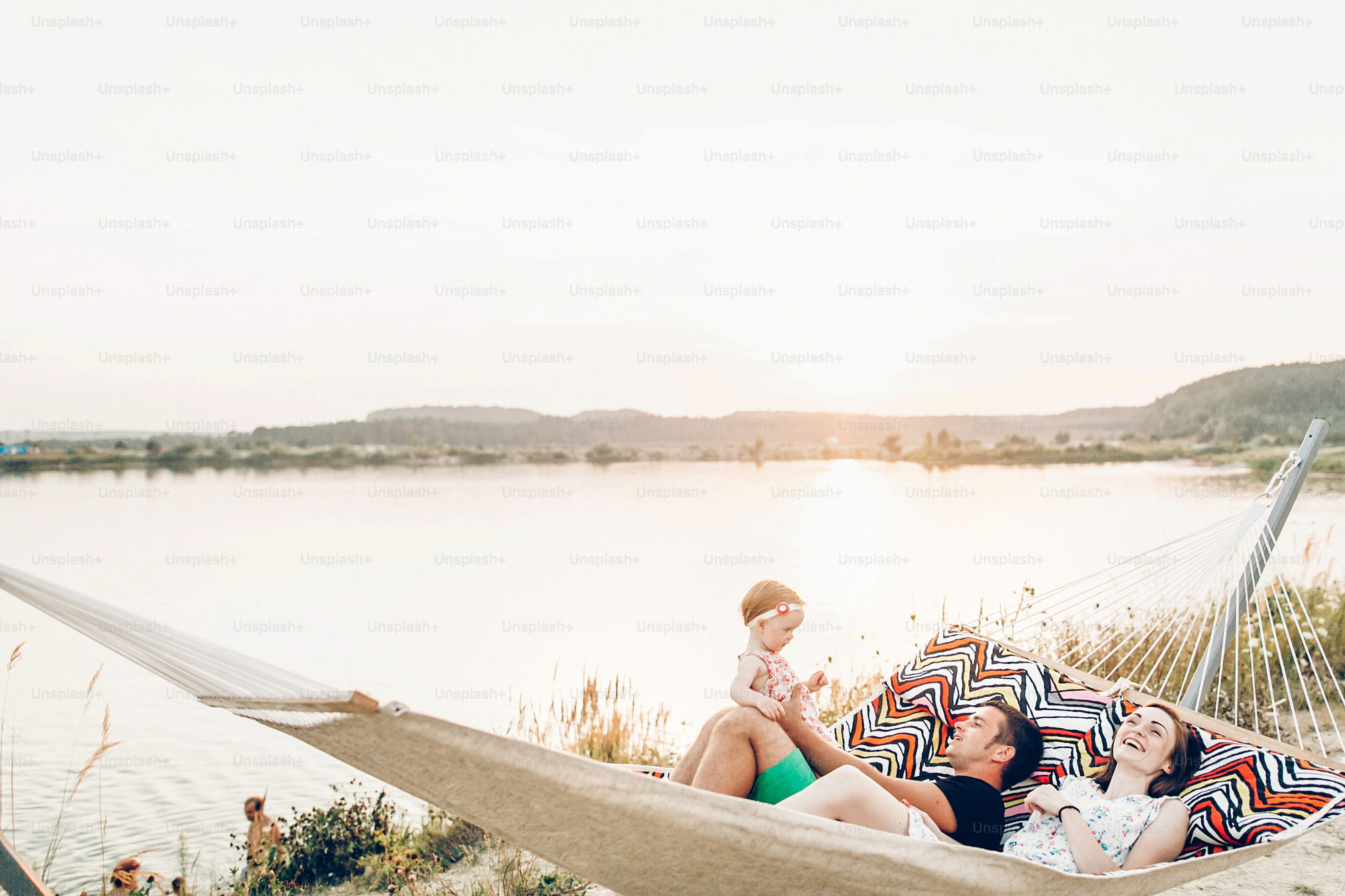 Happy stylish family relaxing in hammock on summer vacation in evening ...