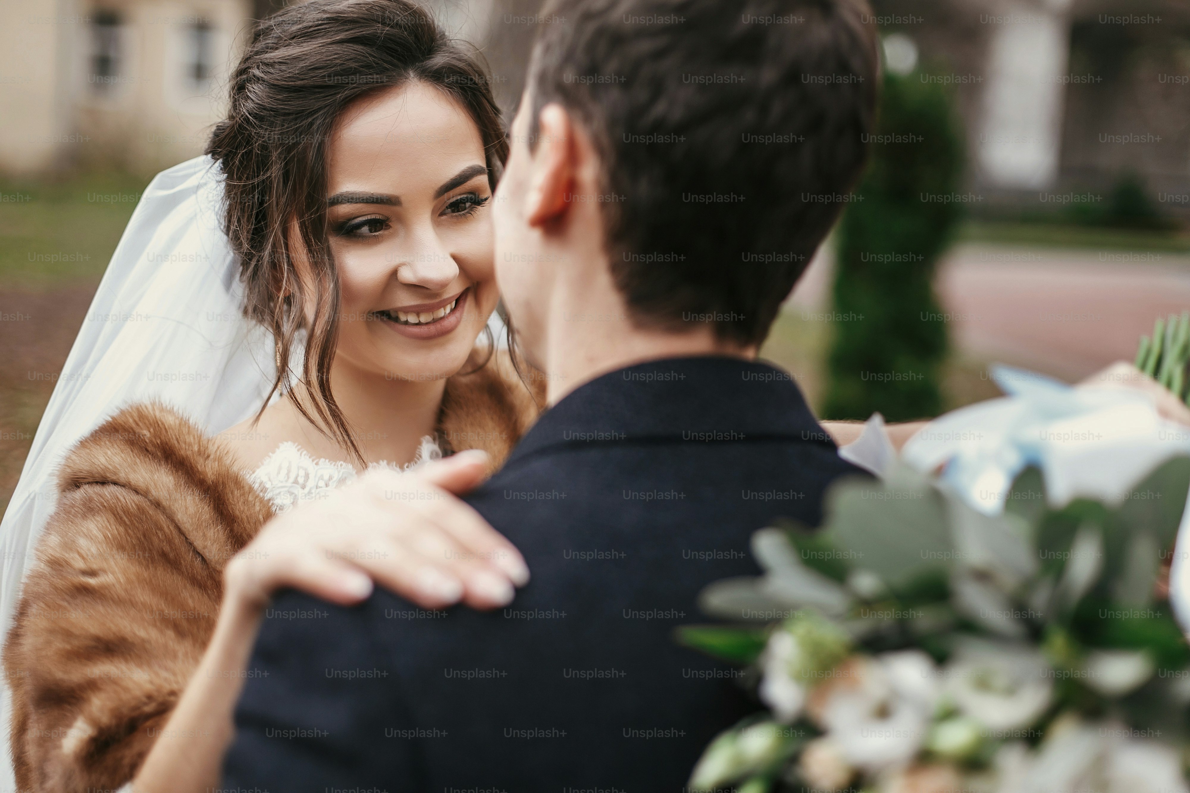 Foto Hermosa novia con ramo mirando al elegante novio abrazando ...