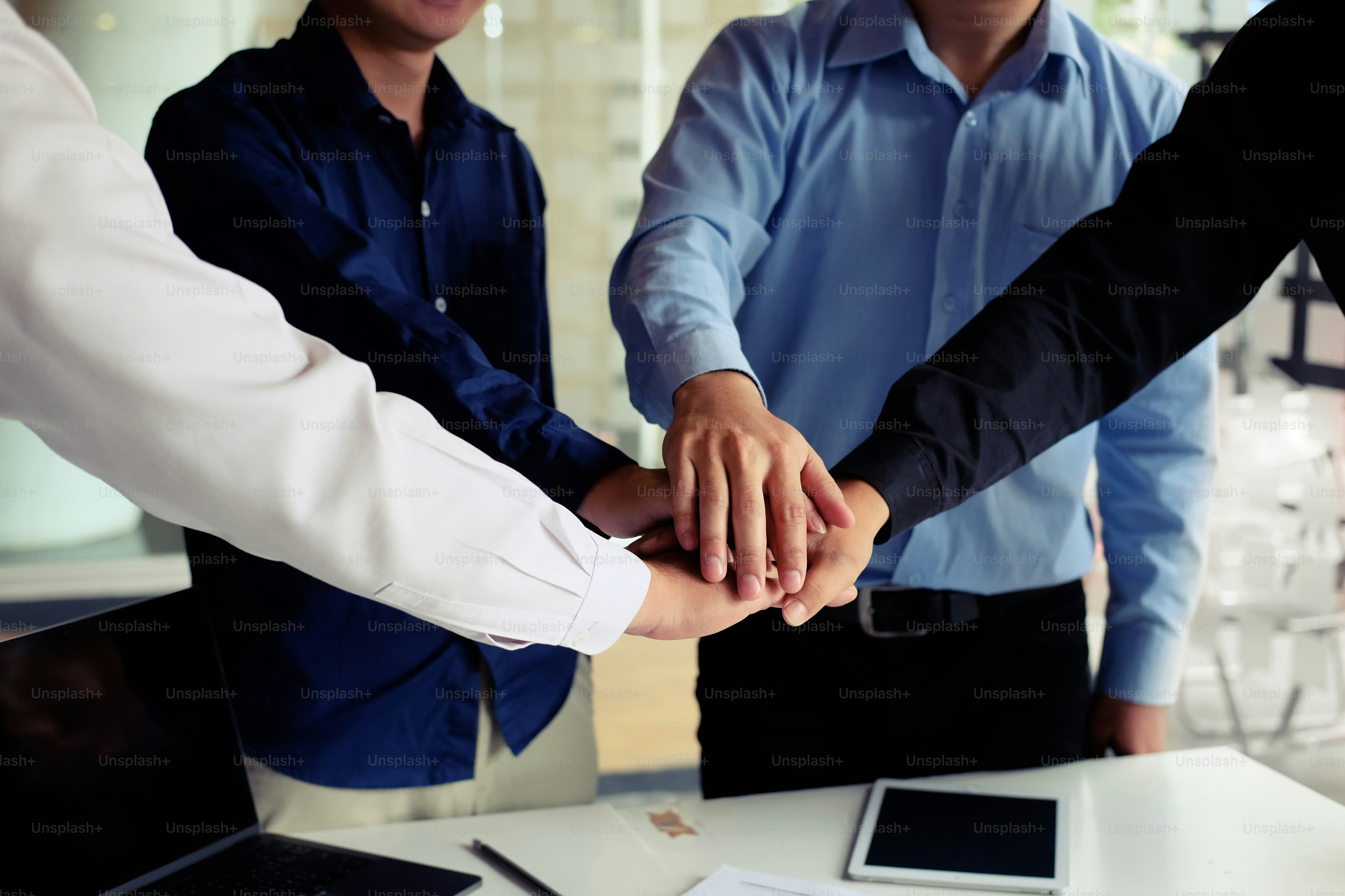 Business people putting their hands on top of office desk cooperation ...