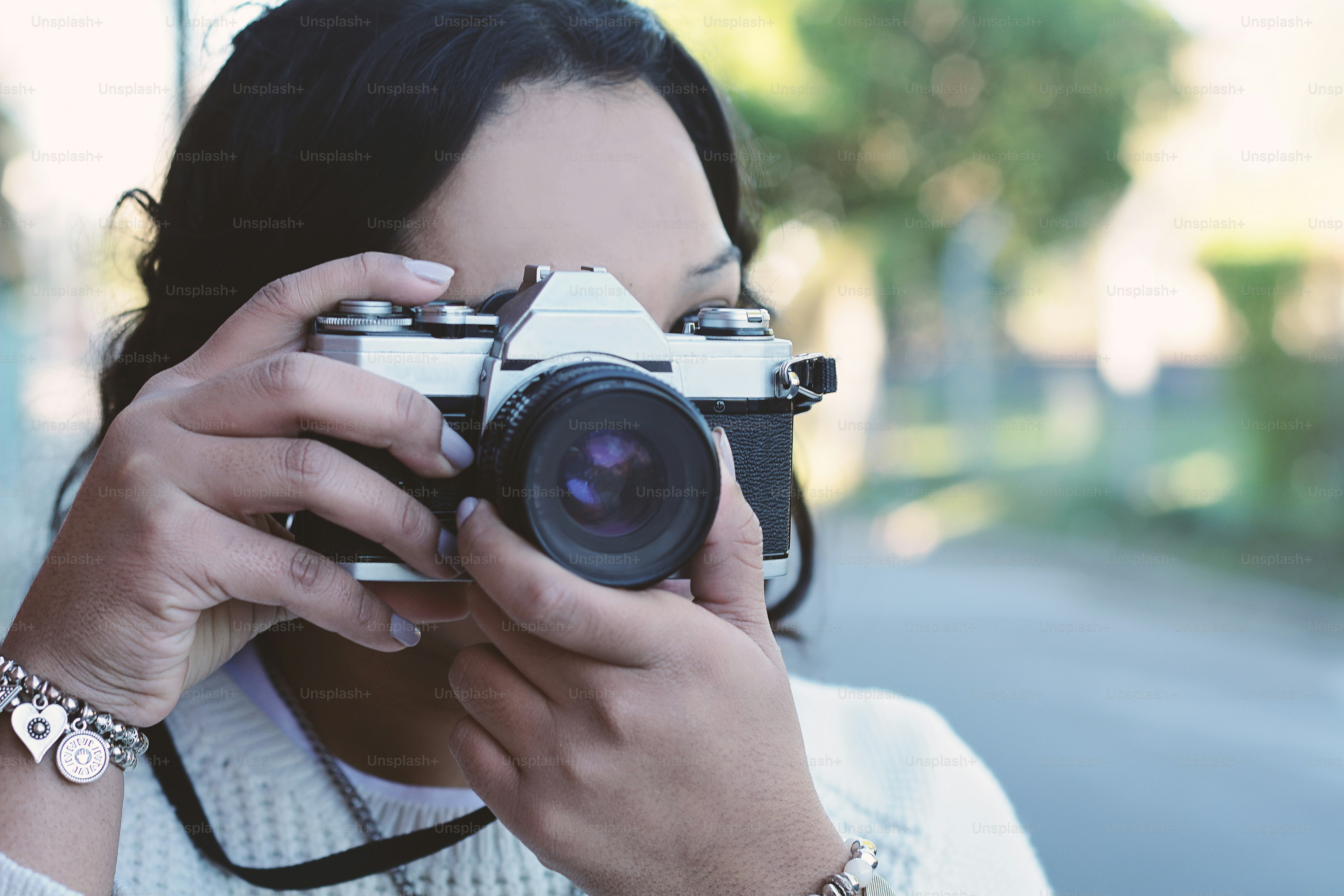 Portrait of young woman having fun taking photos with retro film camera ...