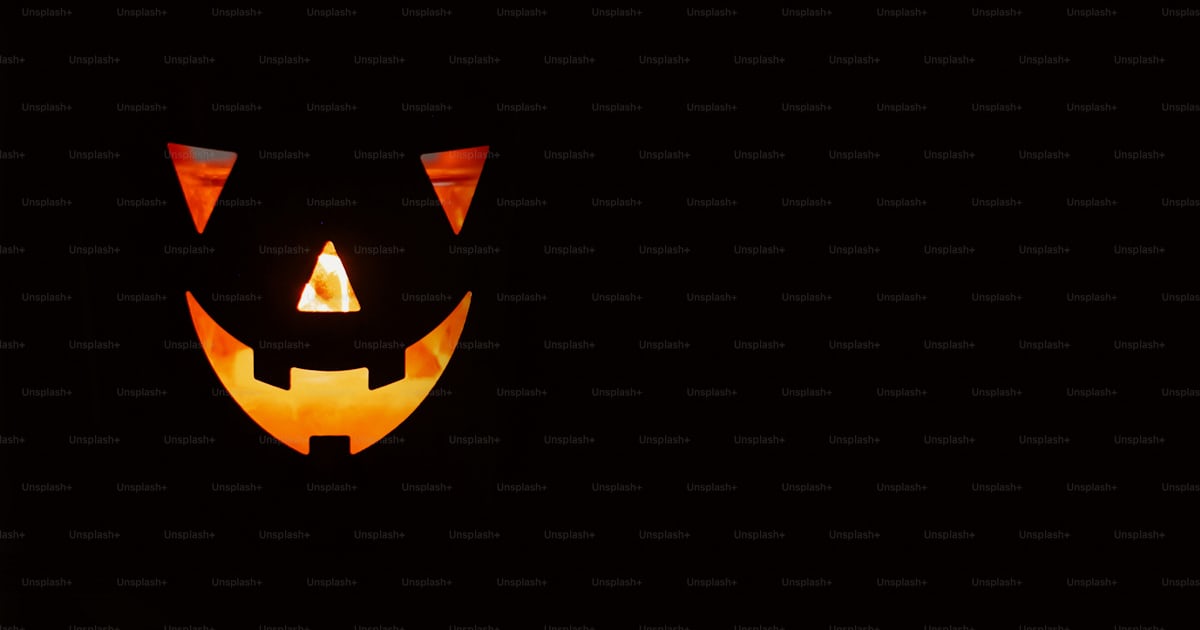 黒い背景に恐ろしい光る顔を持つハロウィーンのカボチャが分離されました。暗闇の中で光るカボチャのジャック・オー・ランタン。お菓子をくれないと