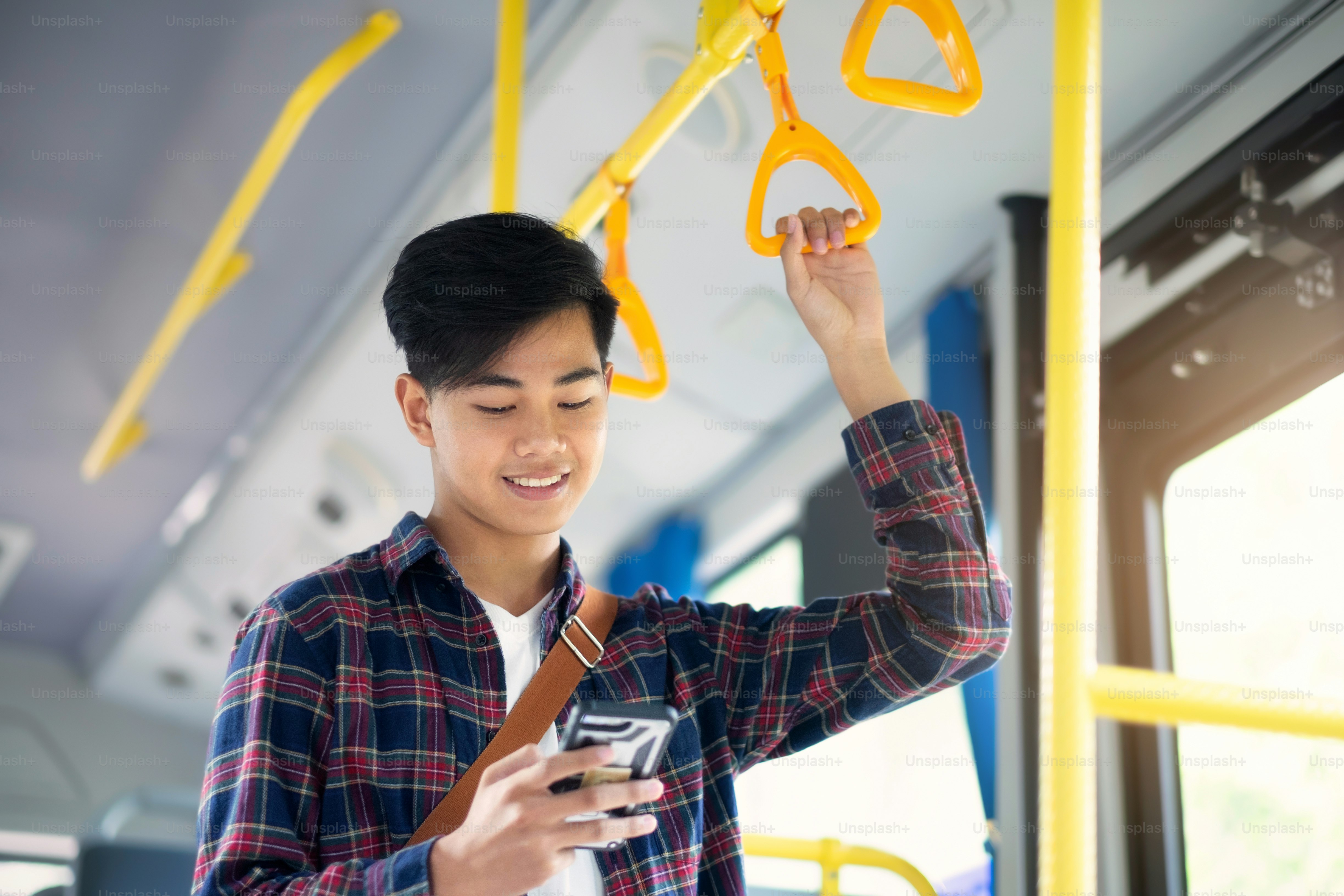 Young asian male passenger using mobile phone on public bus. photo ...