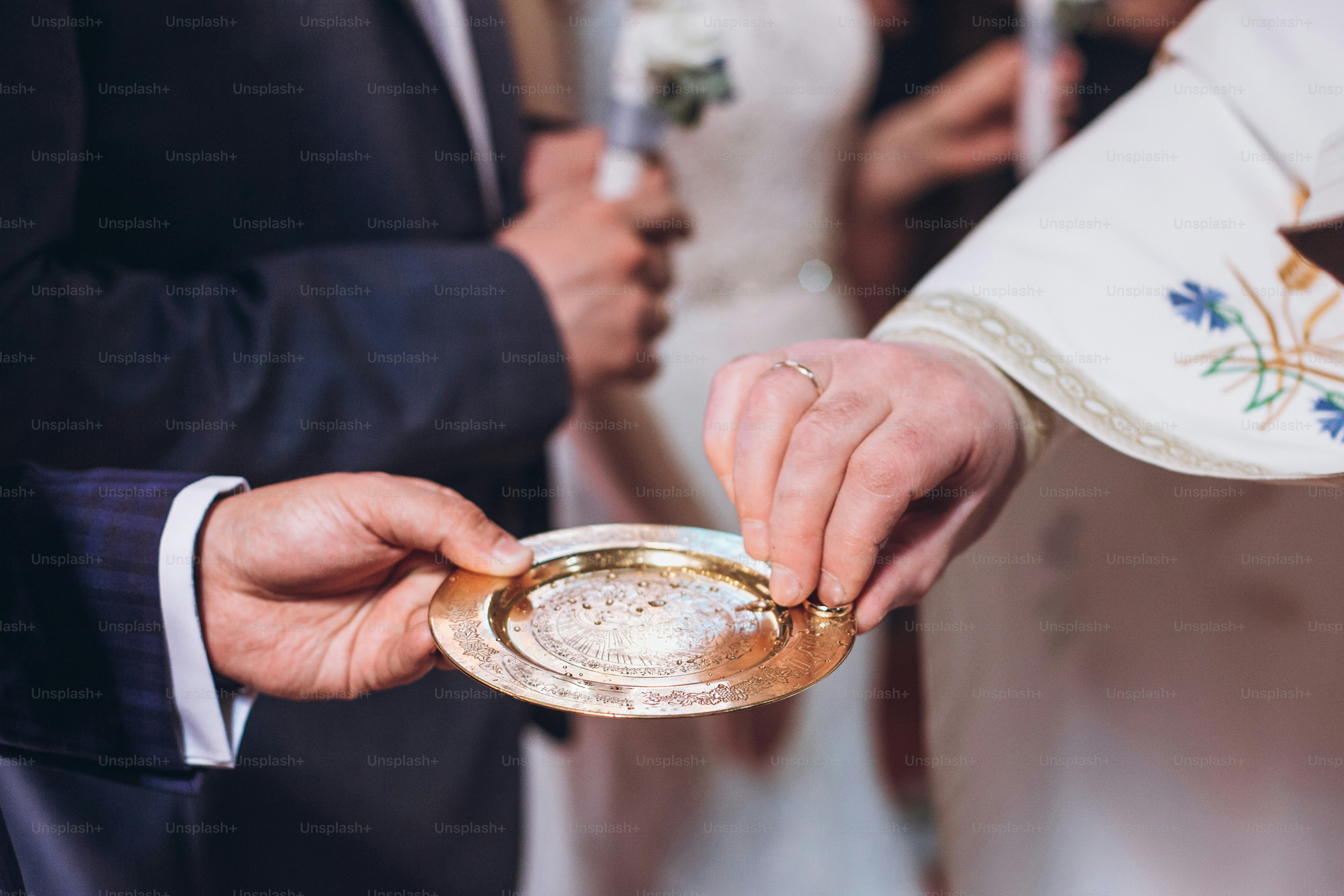 Priest golding golden wedding rings on plate in church at wedding ...