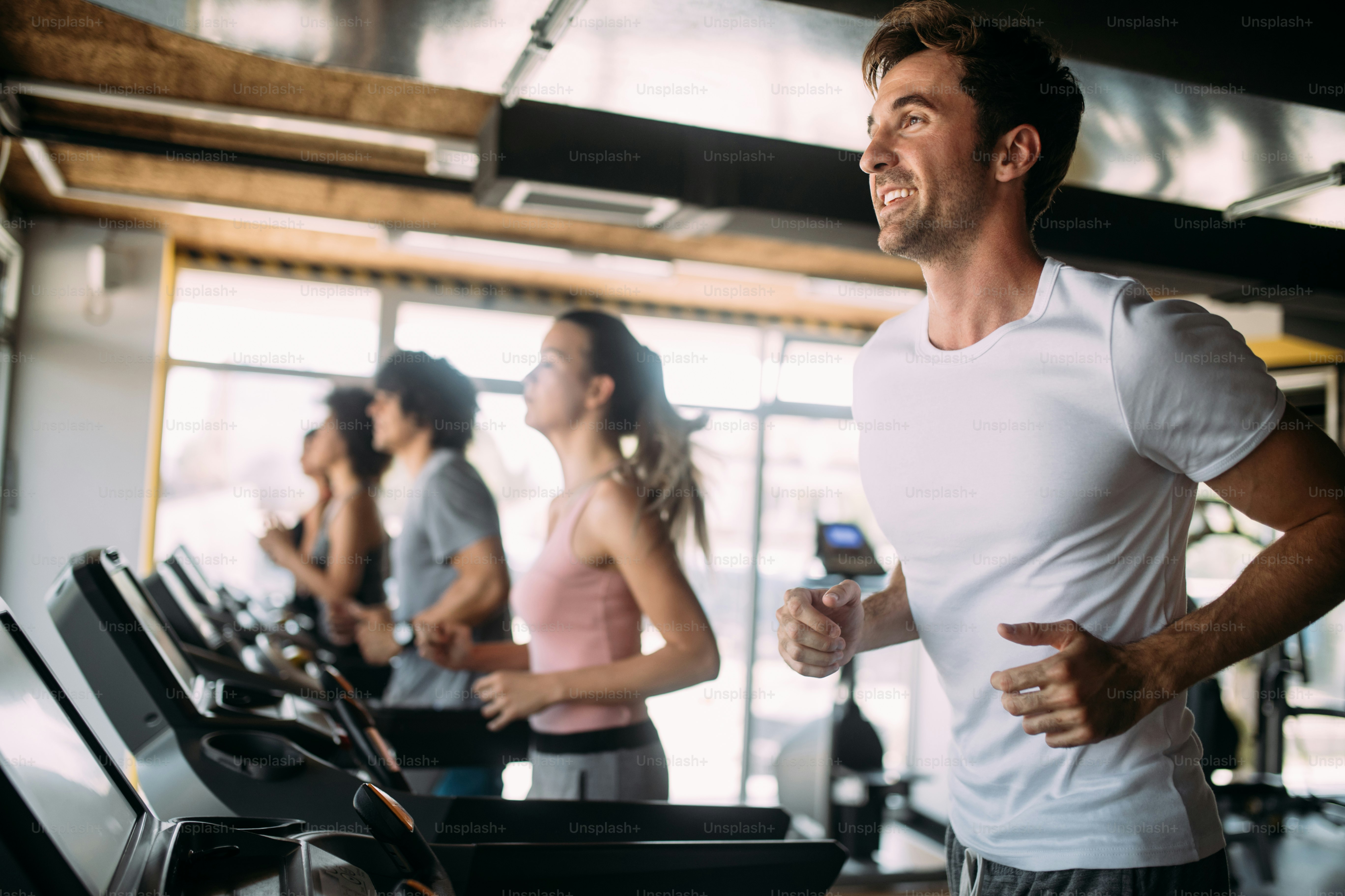 Young fit people running on a treadmill in health club. photo ...