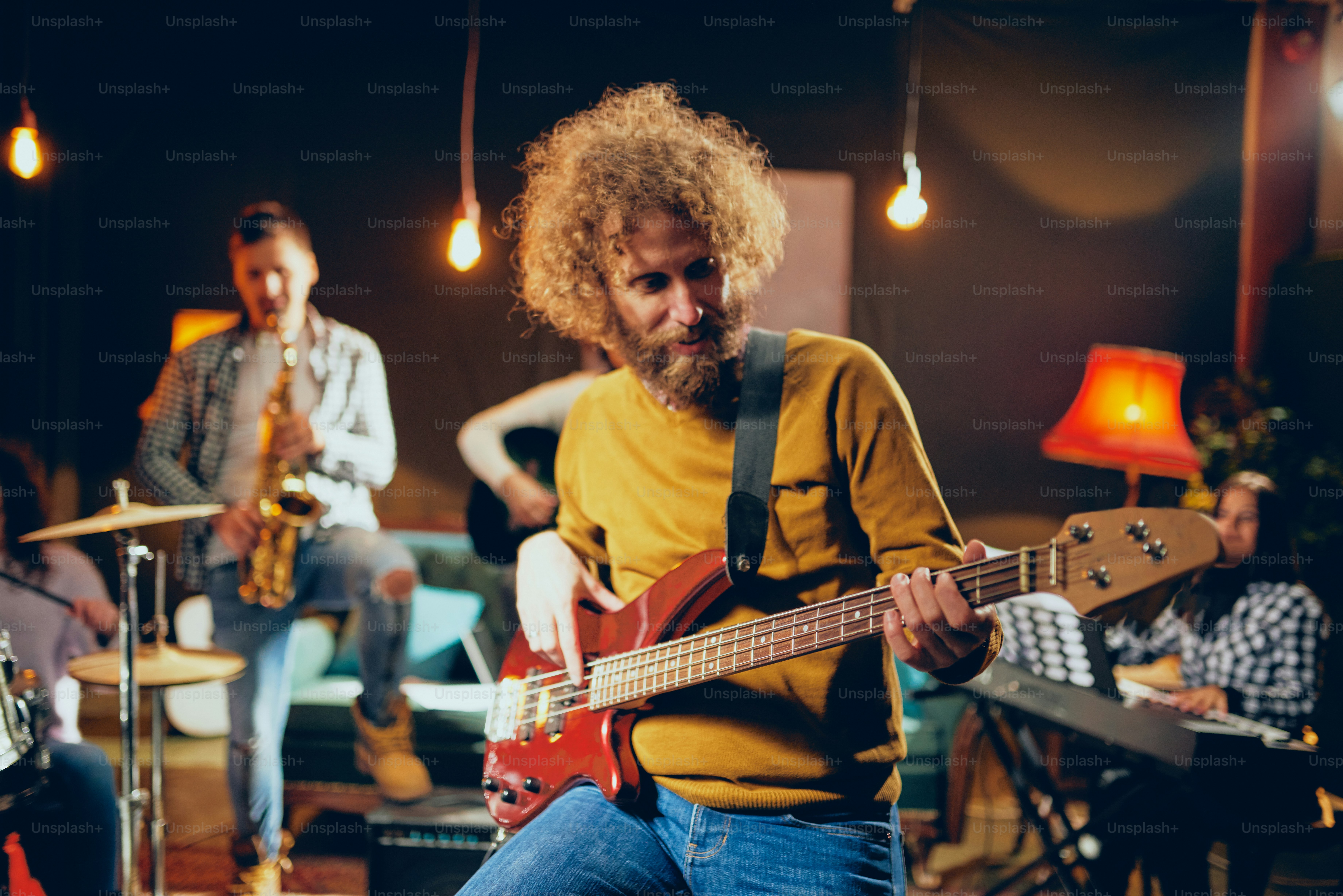 Close up of bass guitarist playing guitar while sitting on the chair ...