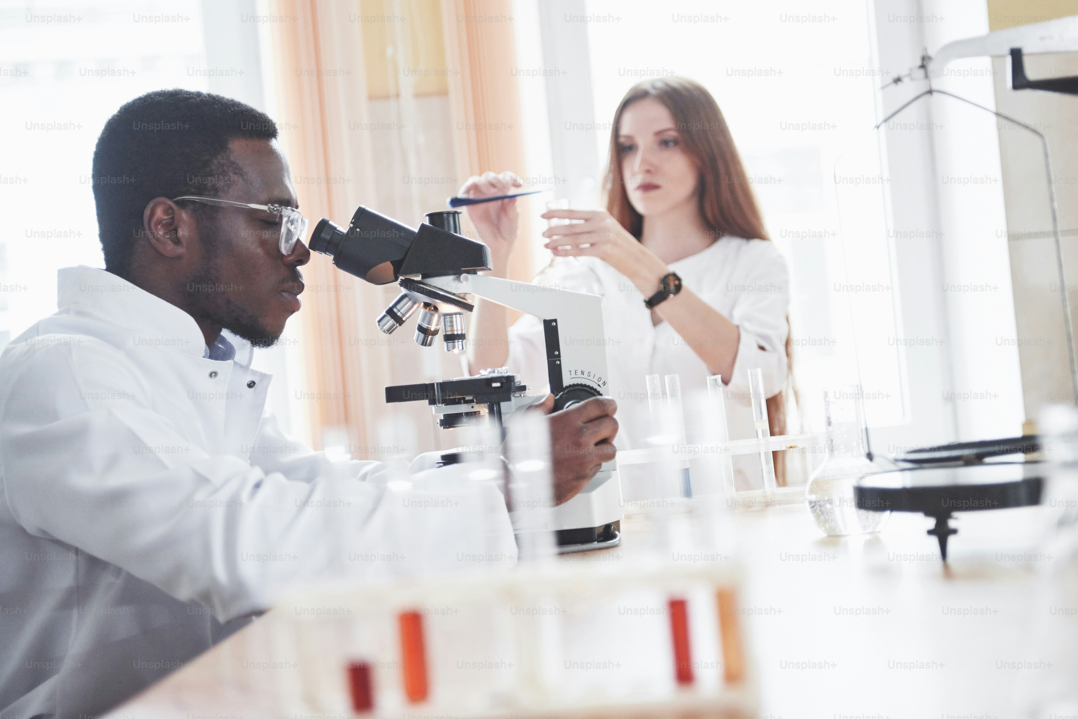 Le scientifique travaille avec un microscope dans un laboratoire pour ...