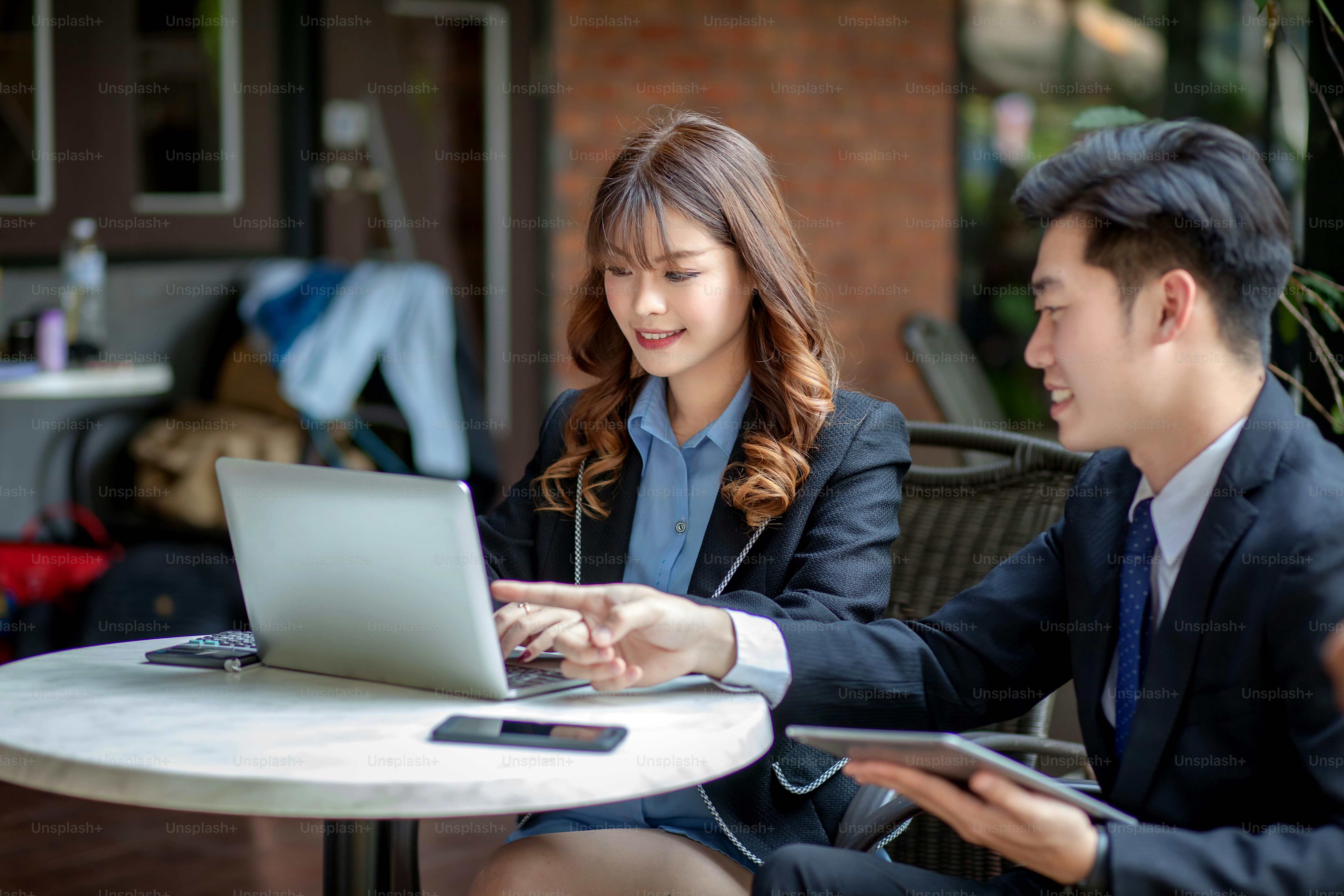 Two business people using laptop and tablet sitting work outdoors ...