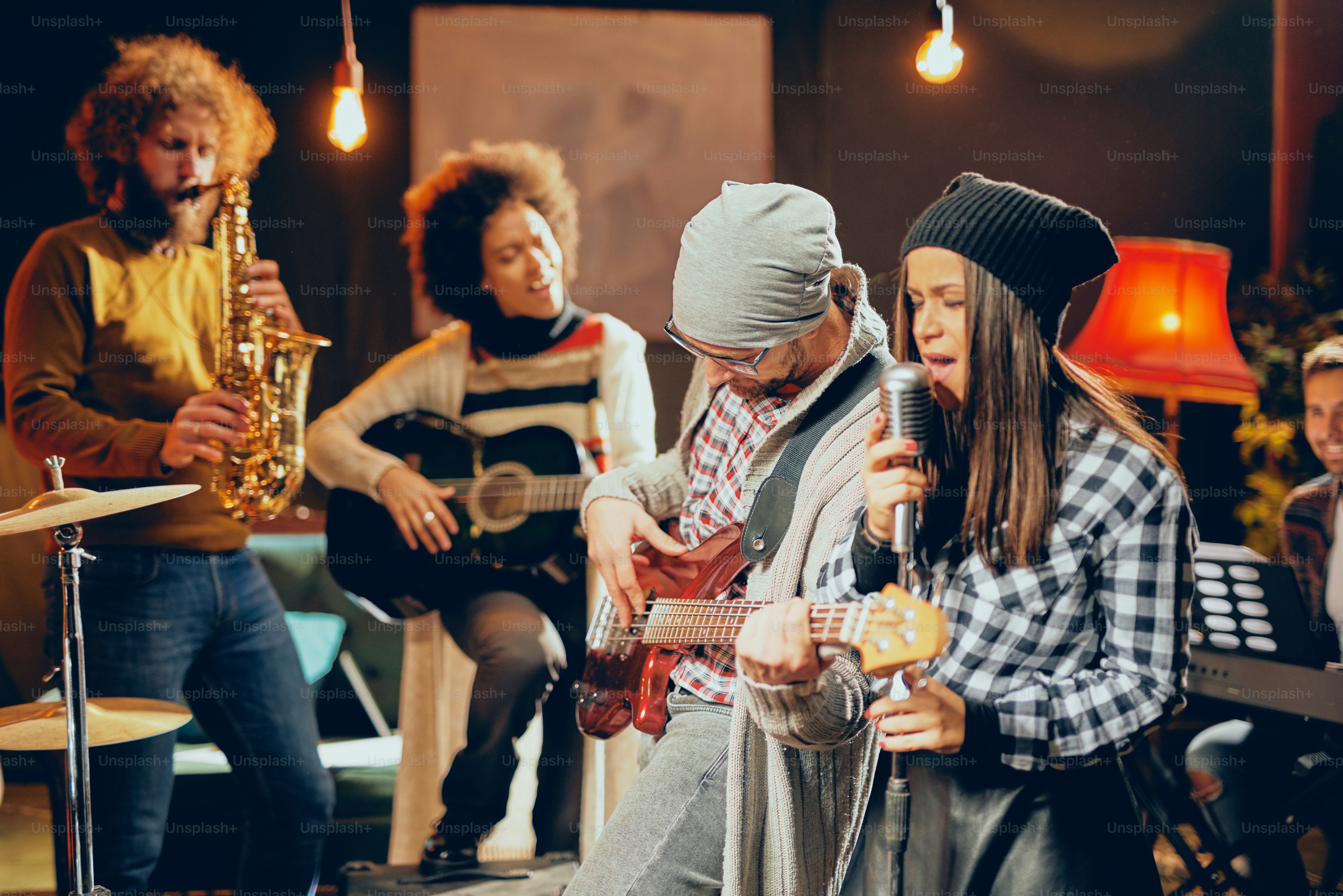 Band practice in home studio. Woman singing while rest of the band ...