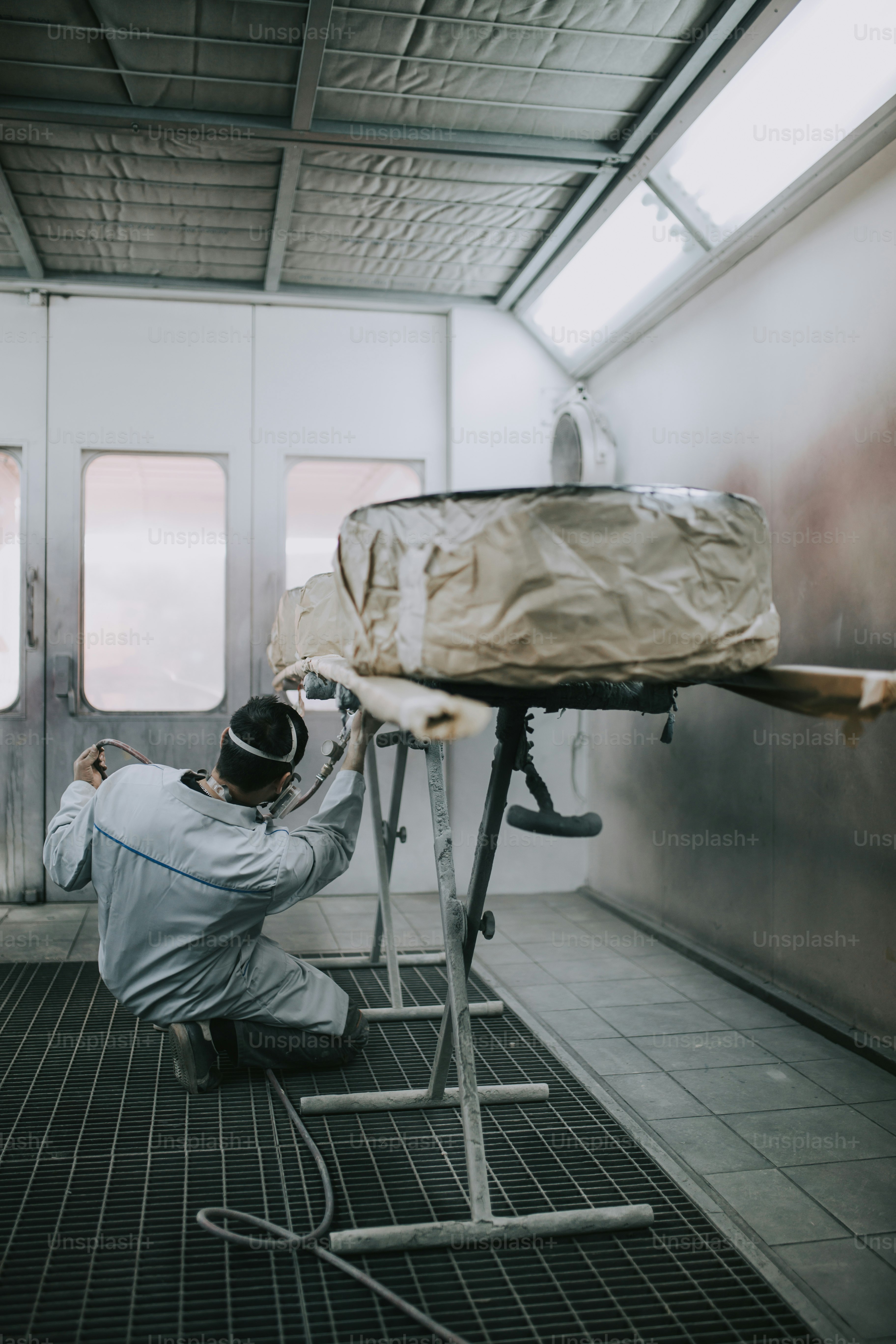 Homme avec des vêtements de protection et un masque peignant des pièces ...