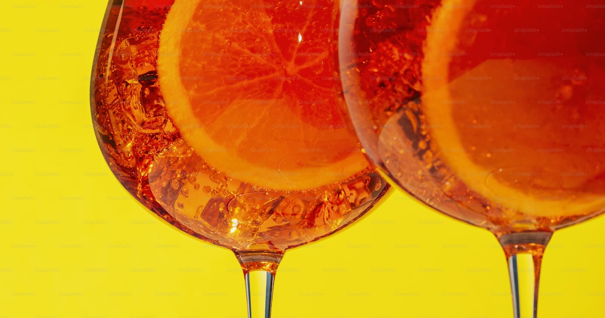 Spritz 노란색 배경에 반짝이는 프로세코 쓴맛 셀츠 오렌지 슬라이스를 곁들인 칵테일 사진 Unsplash의 마시다 이미지