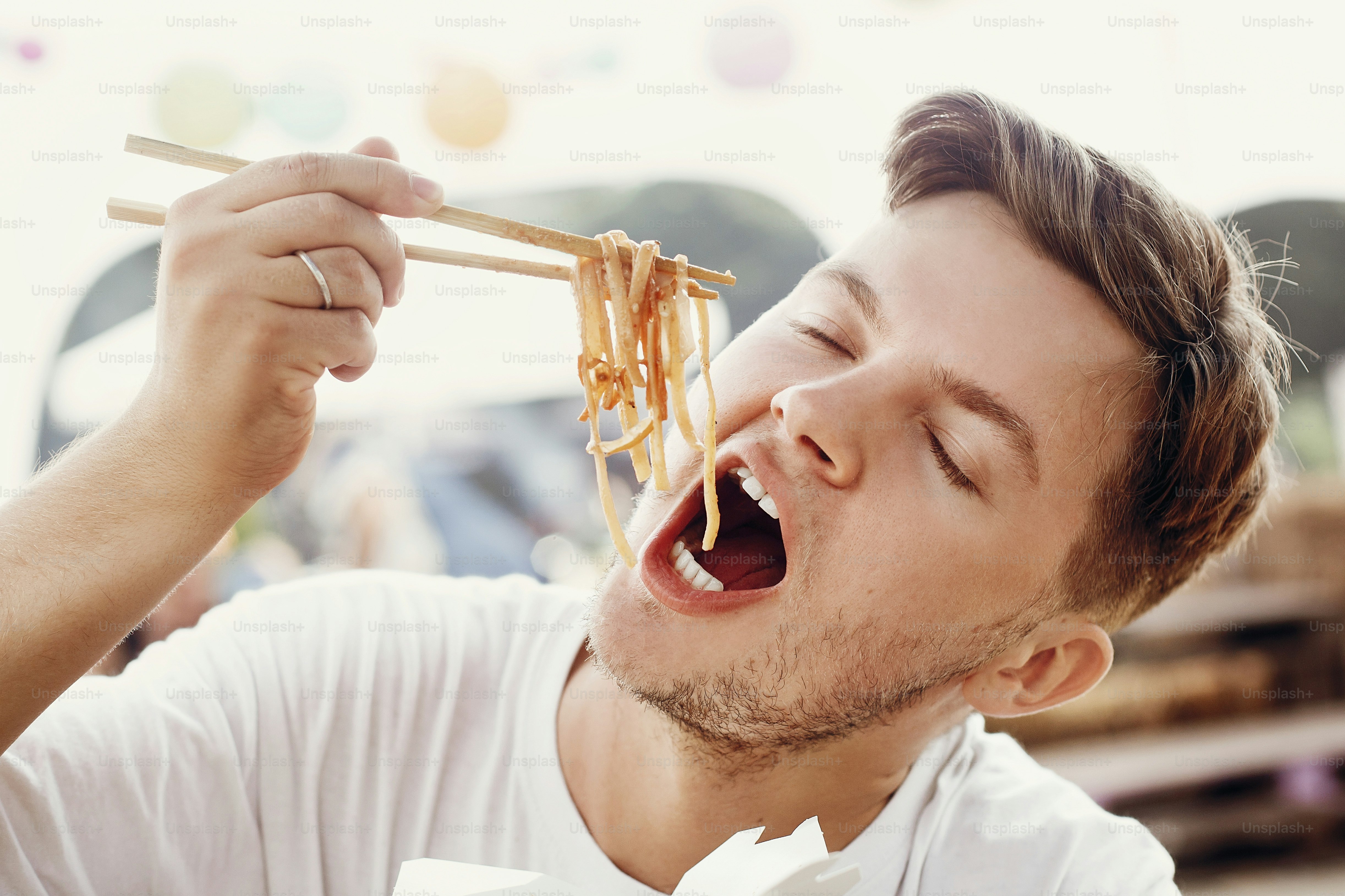 Stylish hungry man eating delicious wok noodles with vegetables from ...