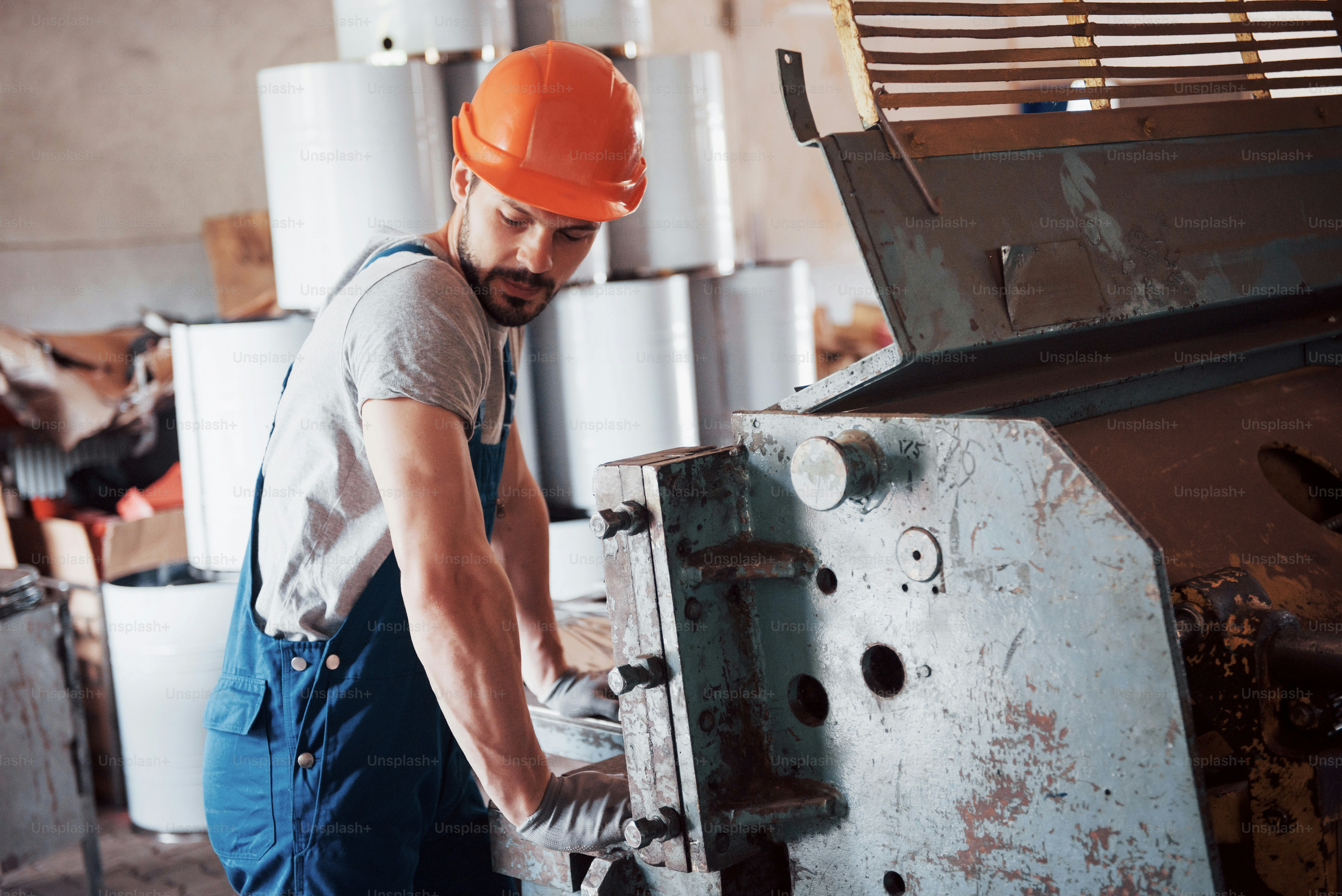 Portrait of a young worker in a hard hat at a large waste recycling ...