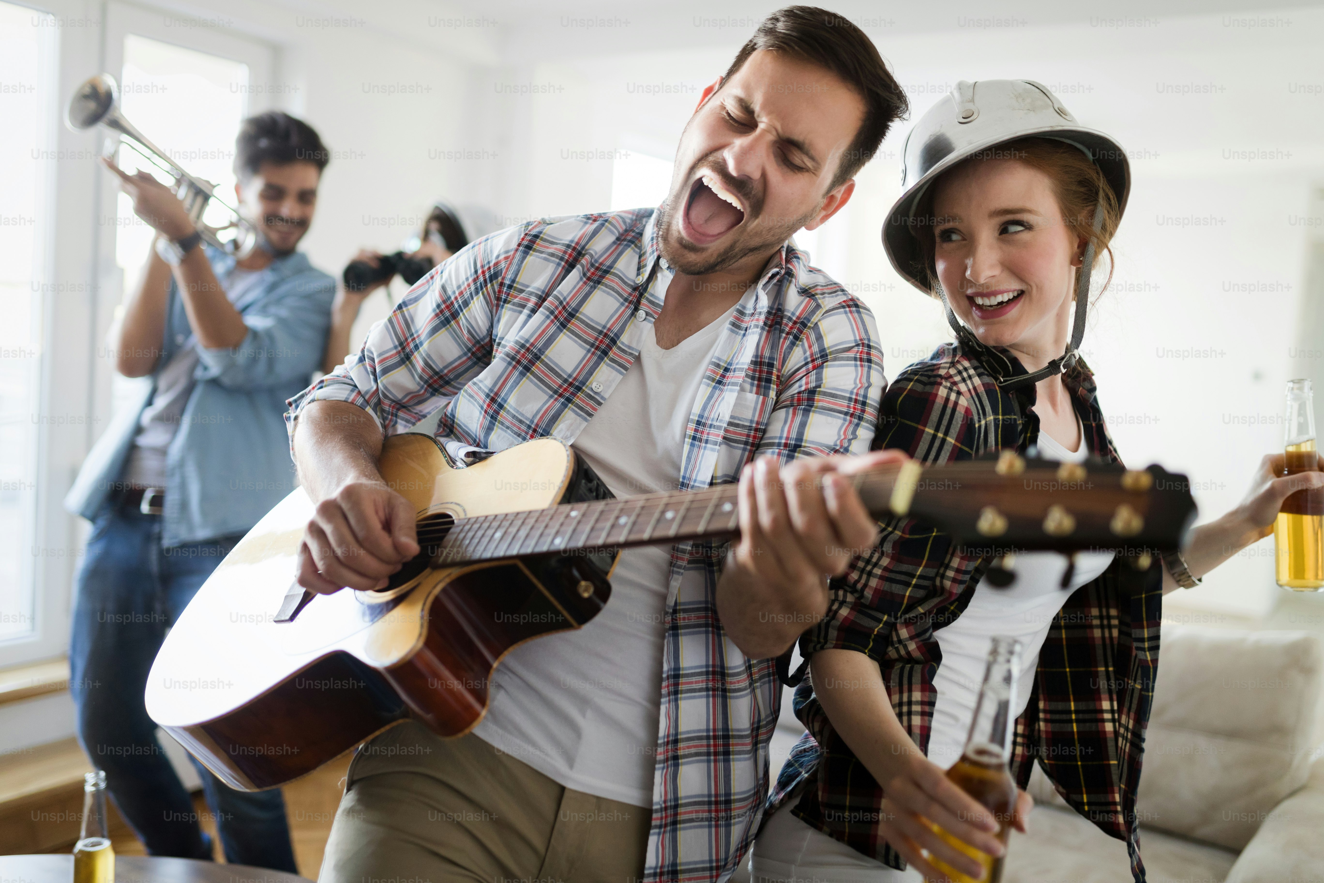 Cheerful happy group of friends having fun while playing instruments ...
