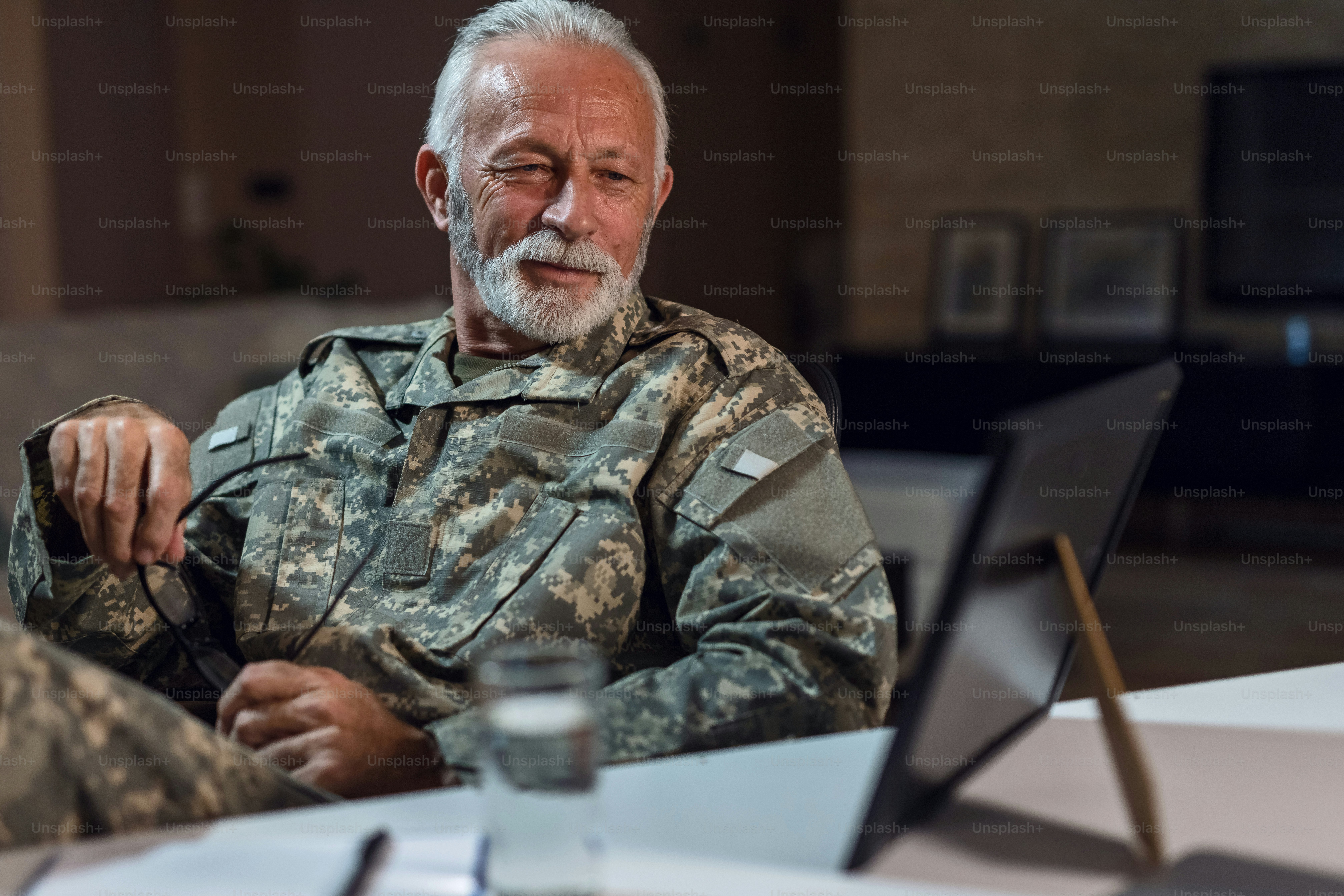 Smiling soldier in military uniform looking at framed photo on his desk ...