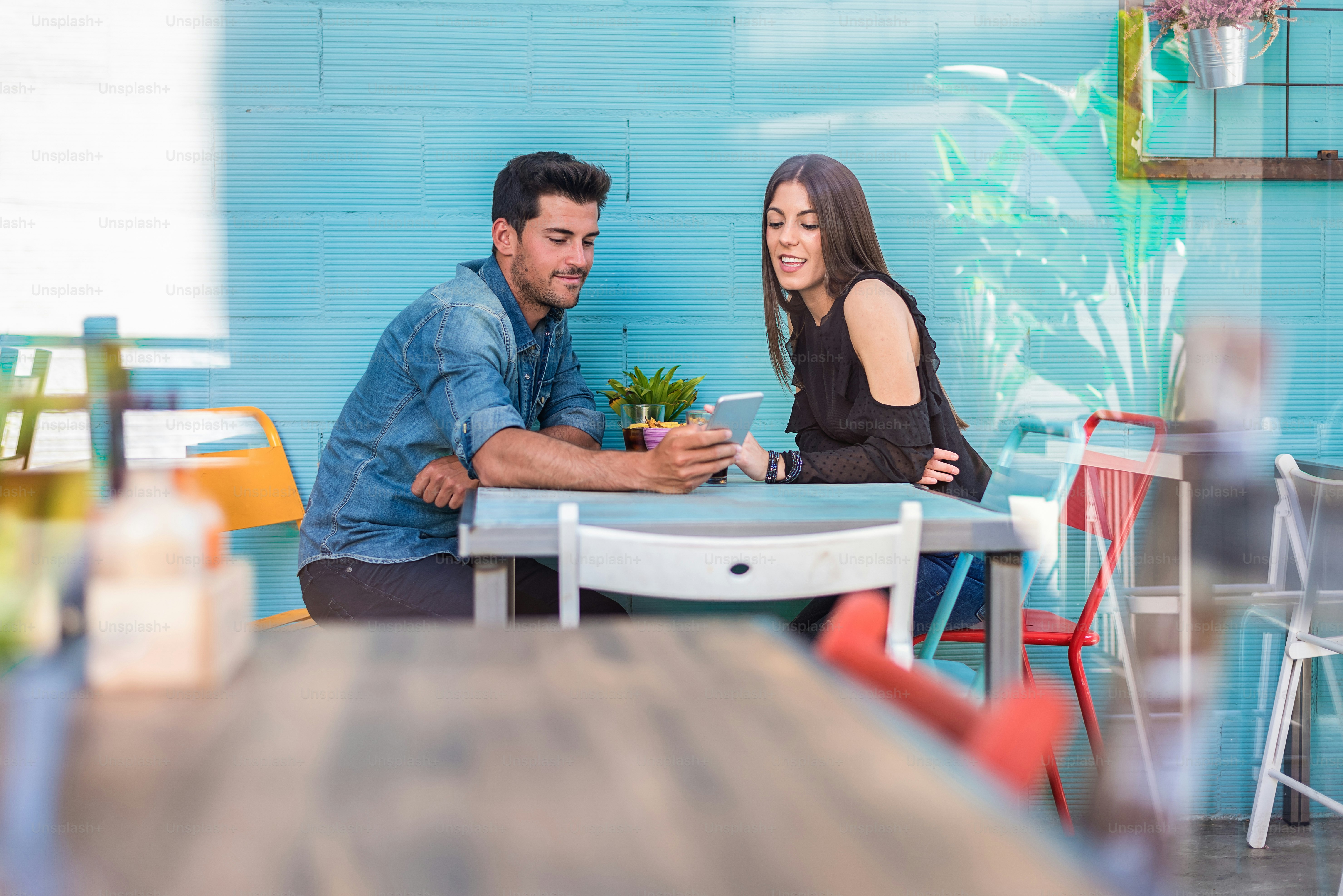 Happy young couple seating in a restaurant with a smartphone photo ...